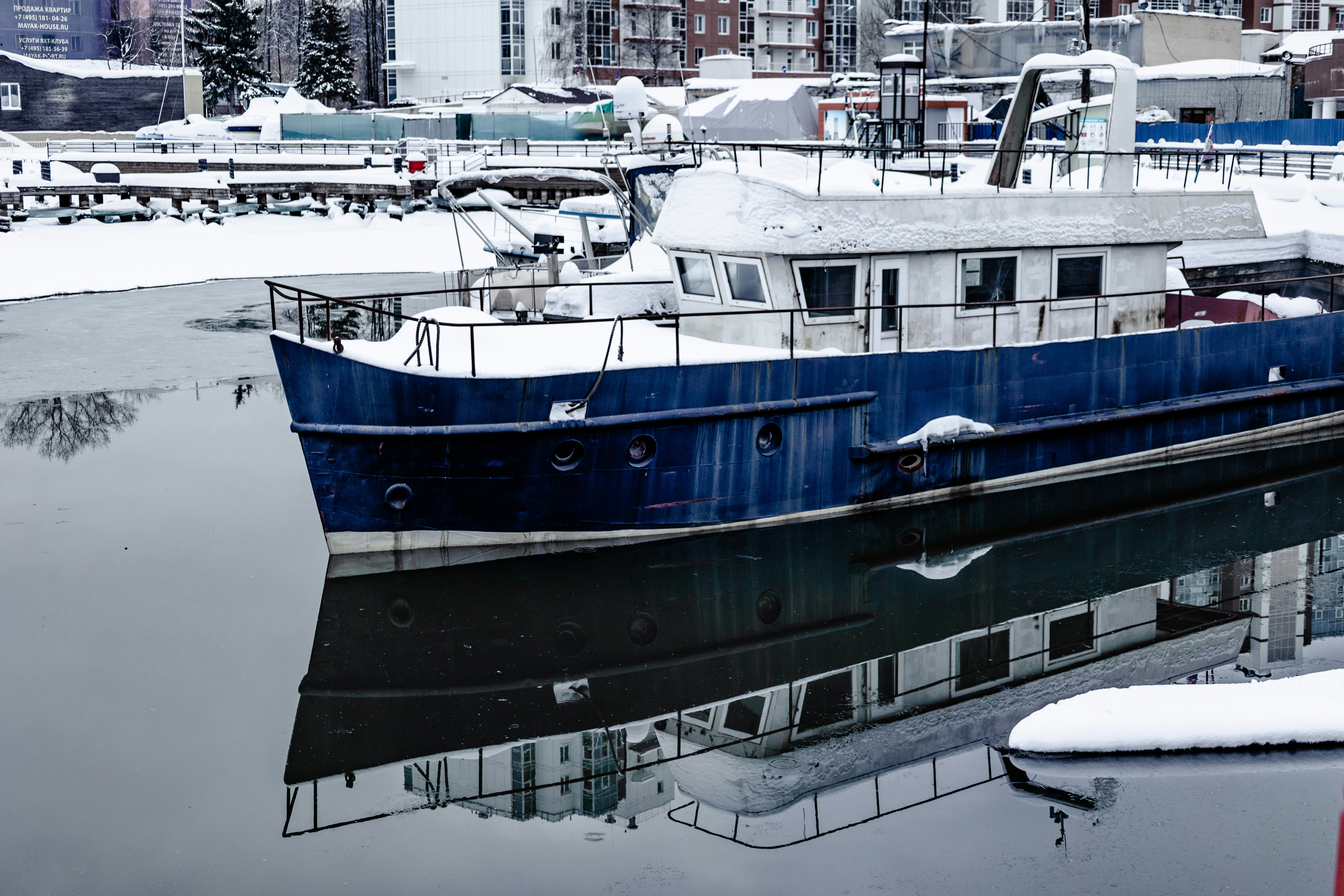 a blue boat is docked in a snowy harbor