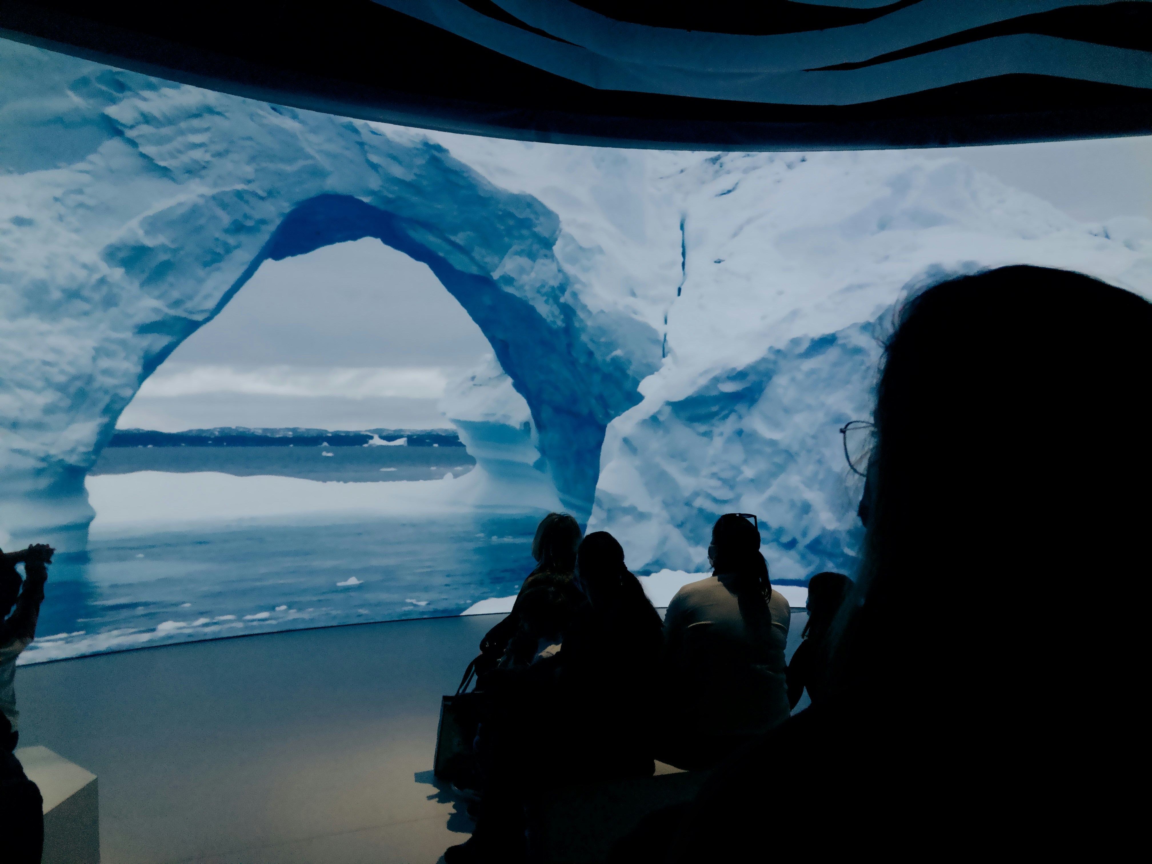 Glacial Archway: Visitors in a Blue Ice Cavern