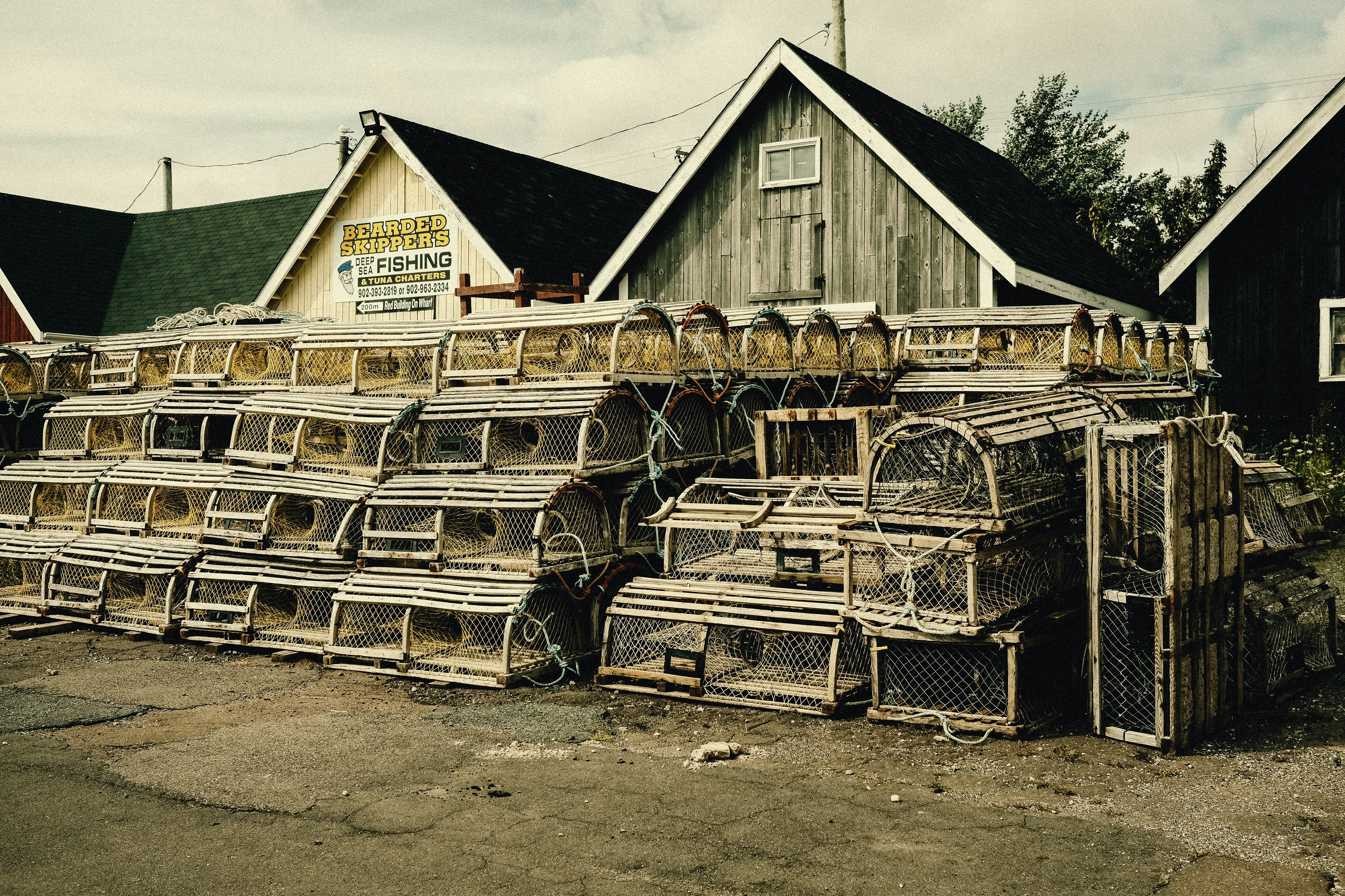 Weathered Lobster Traps Stack Against a Quiet Coastal Village
