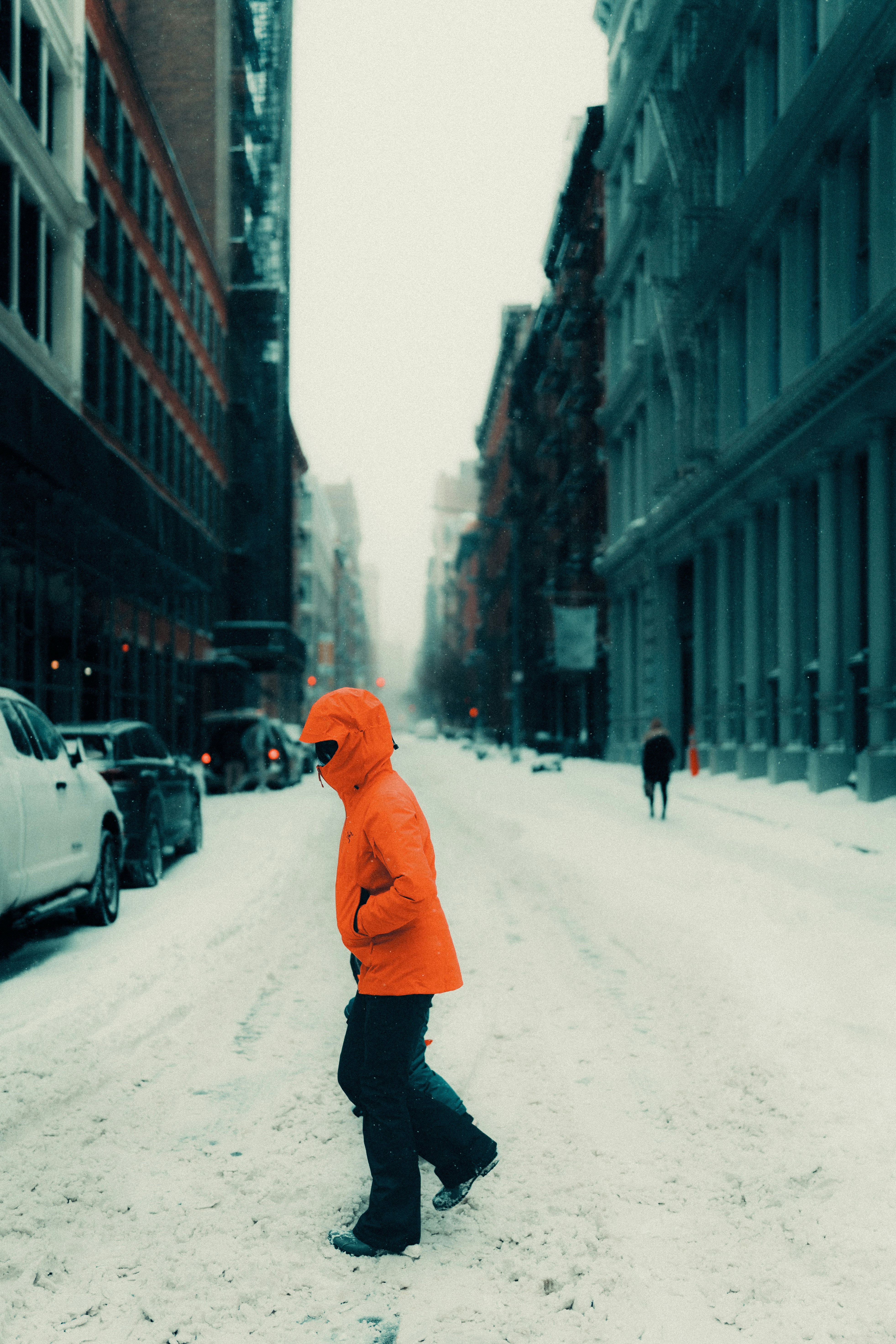 a person in an orange jacket walking down a snowy street