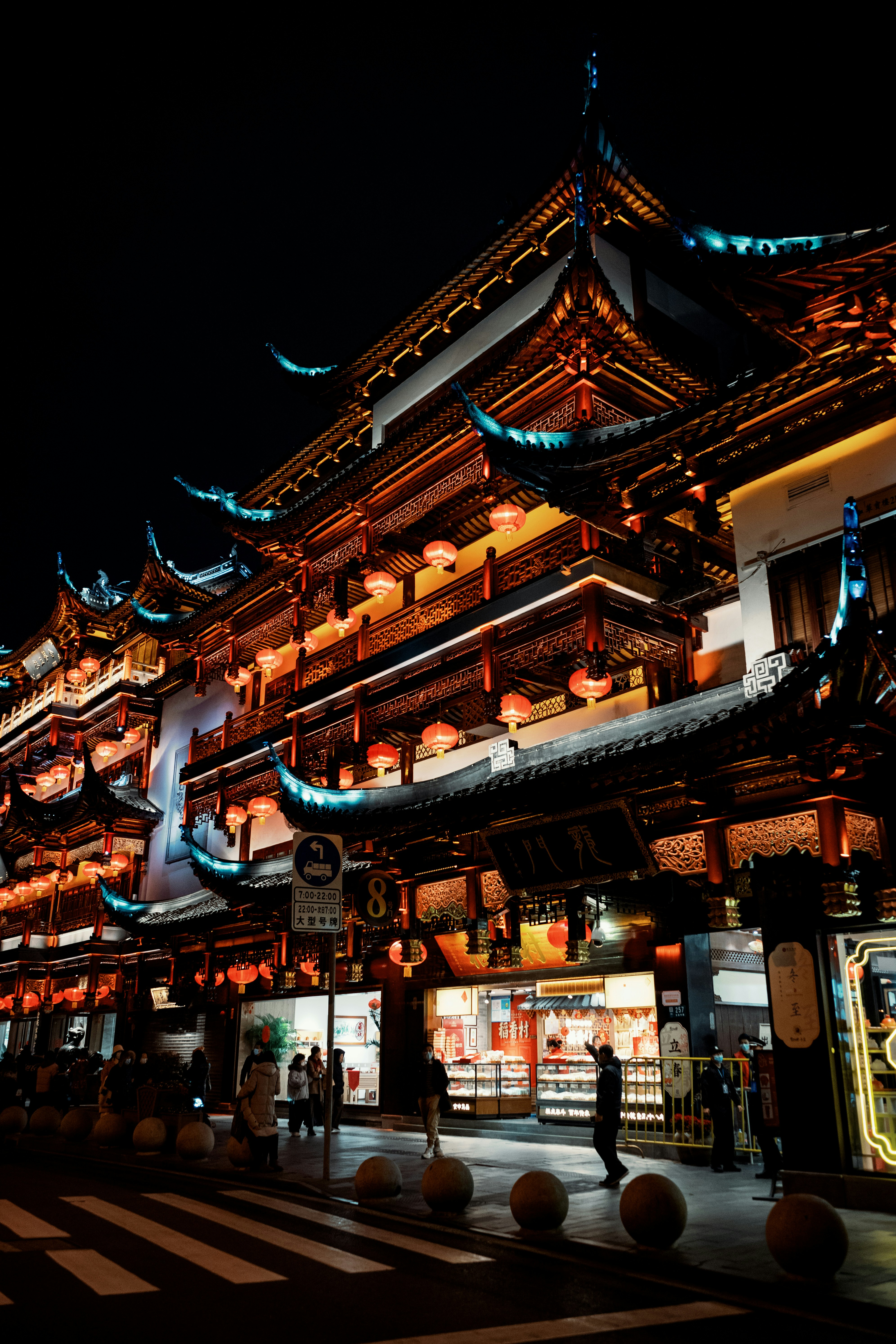 A chinese building lit up at night with people walking around photo ...