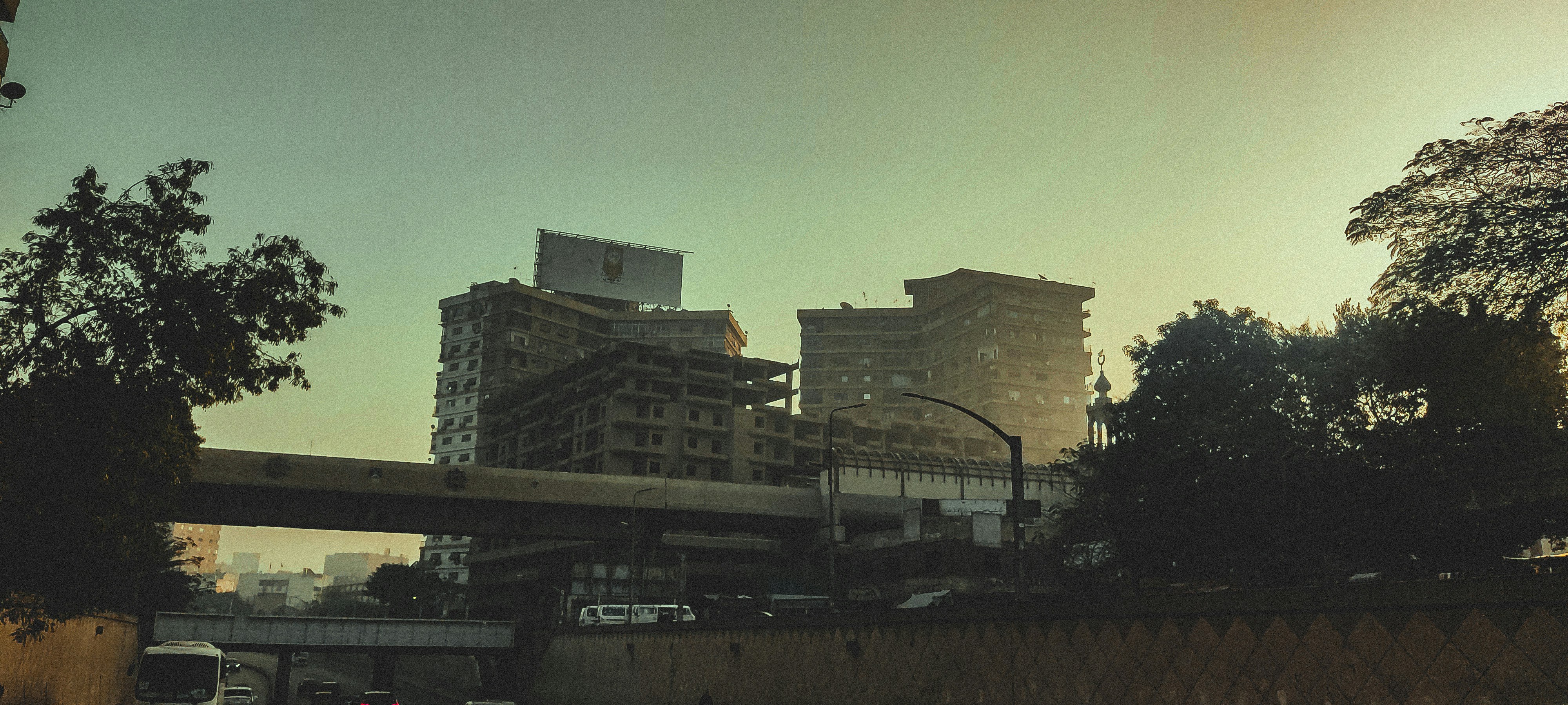 Silhouetted buildings under a hazy sky, showcasing the contrast between nature and urban development.