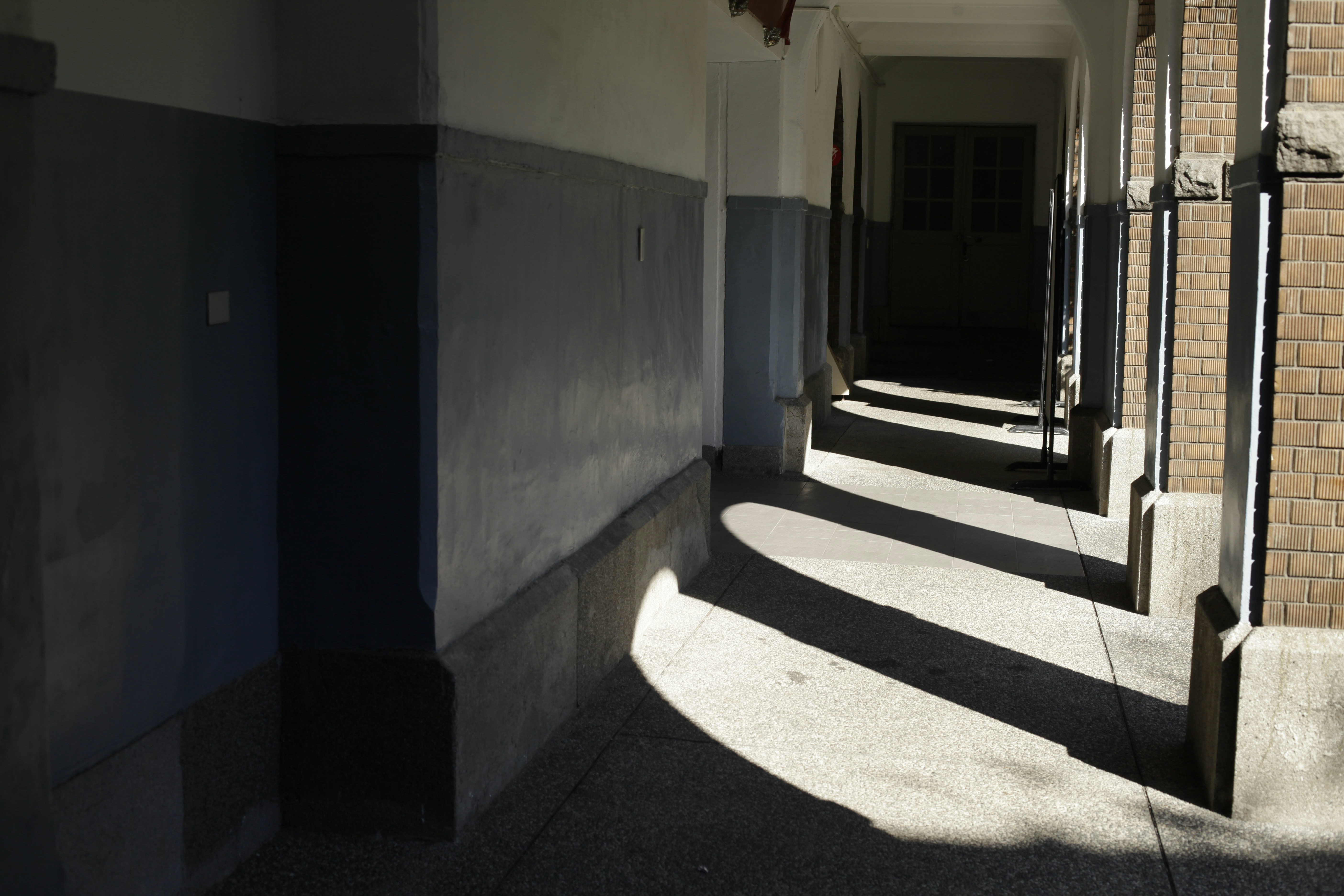 Sunlight casts elongated shadows along a corridor, highlighting the interplay between light and architectural lines.