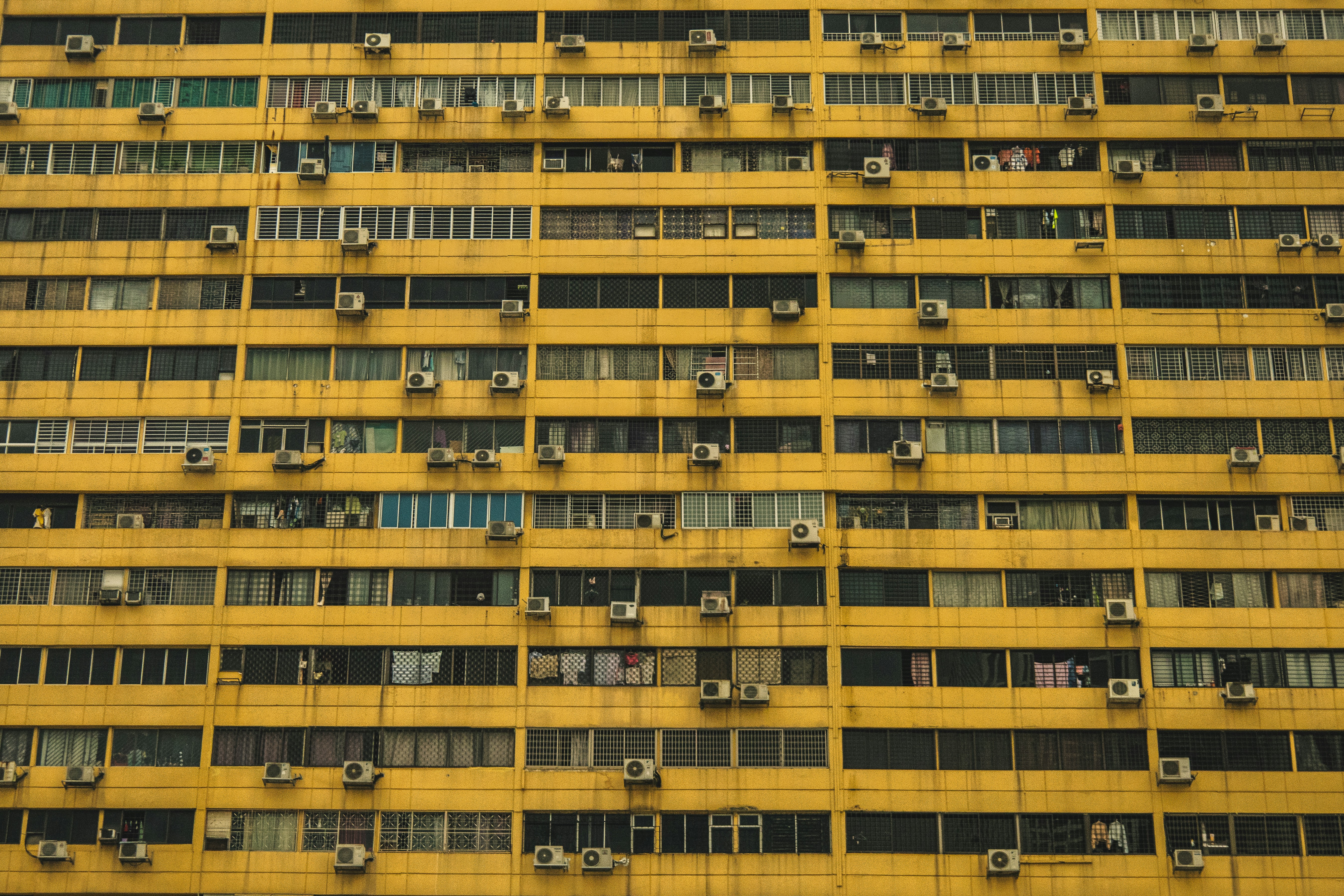 Sunlit Grid: A Yellow Facade of Windows and Air Conditioners