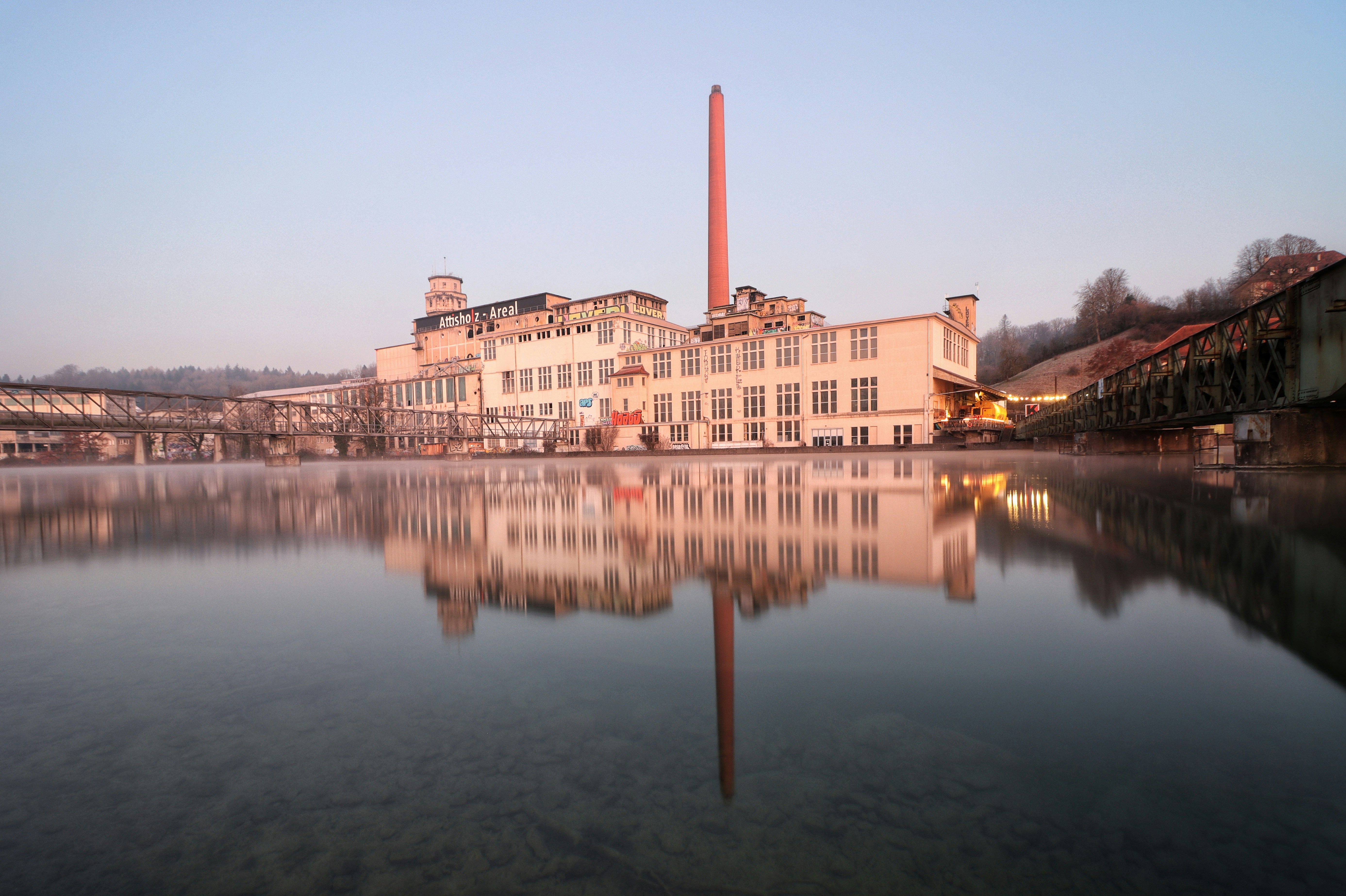 Industrial sunset: mirrored riverbank and smokestack