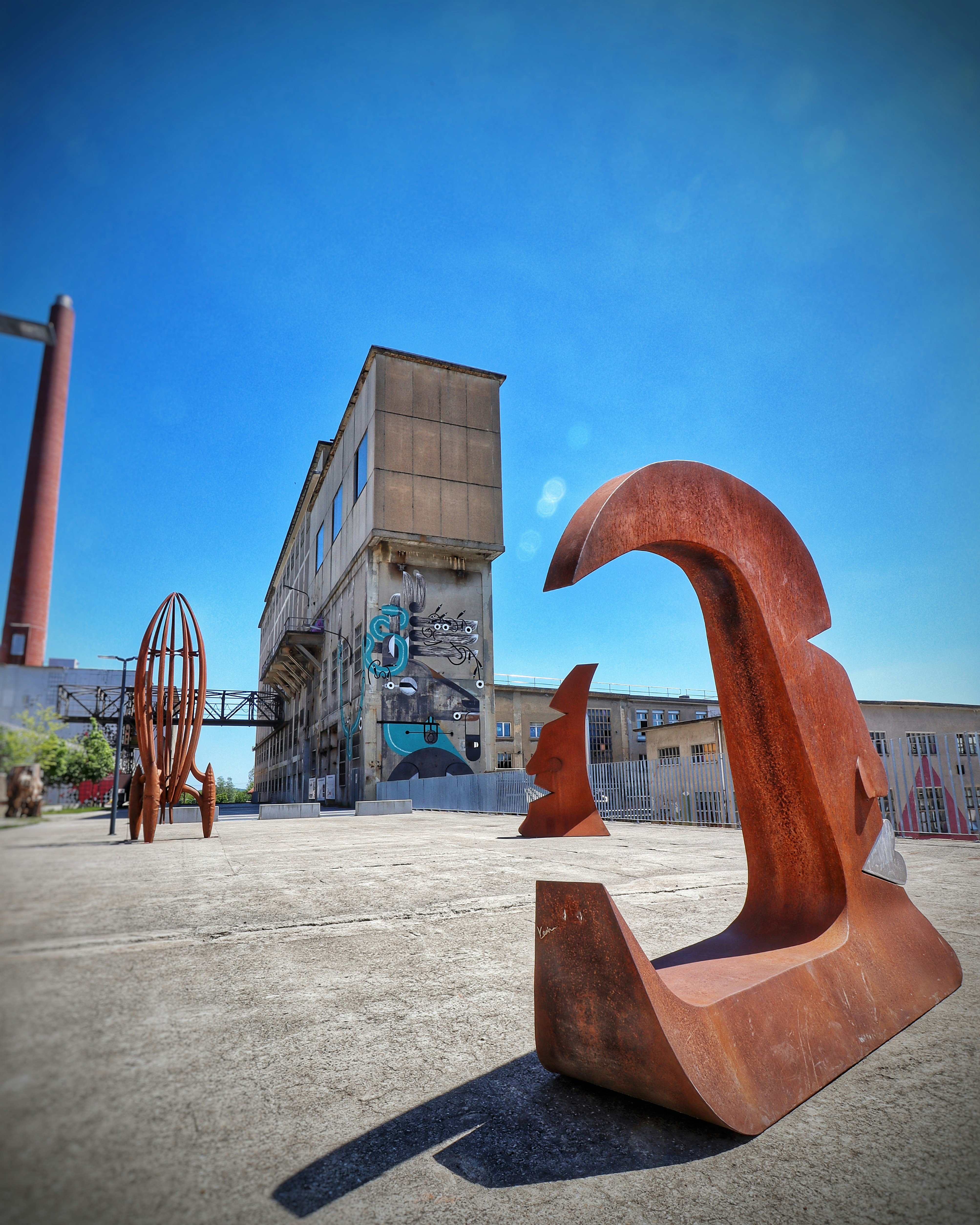 Industrial Echoes: Rusted Sculptures Against a Clear Blue Sky