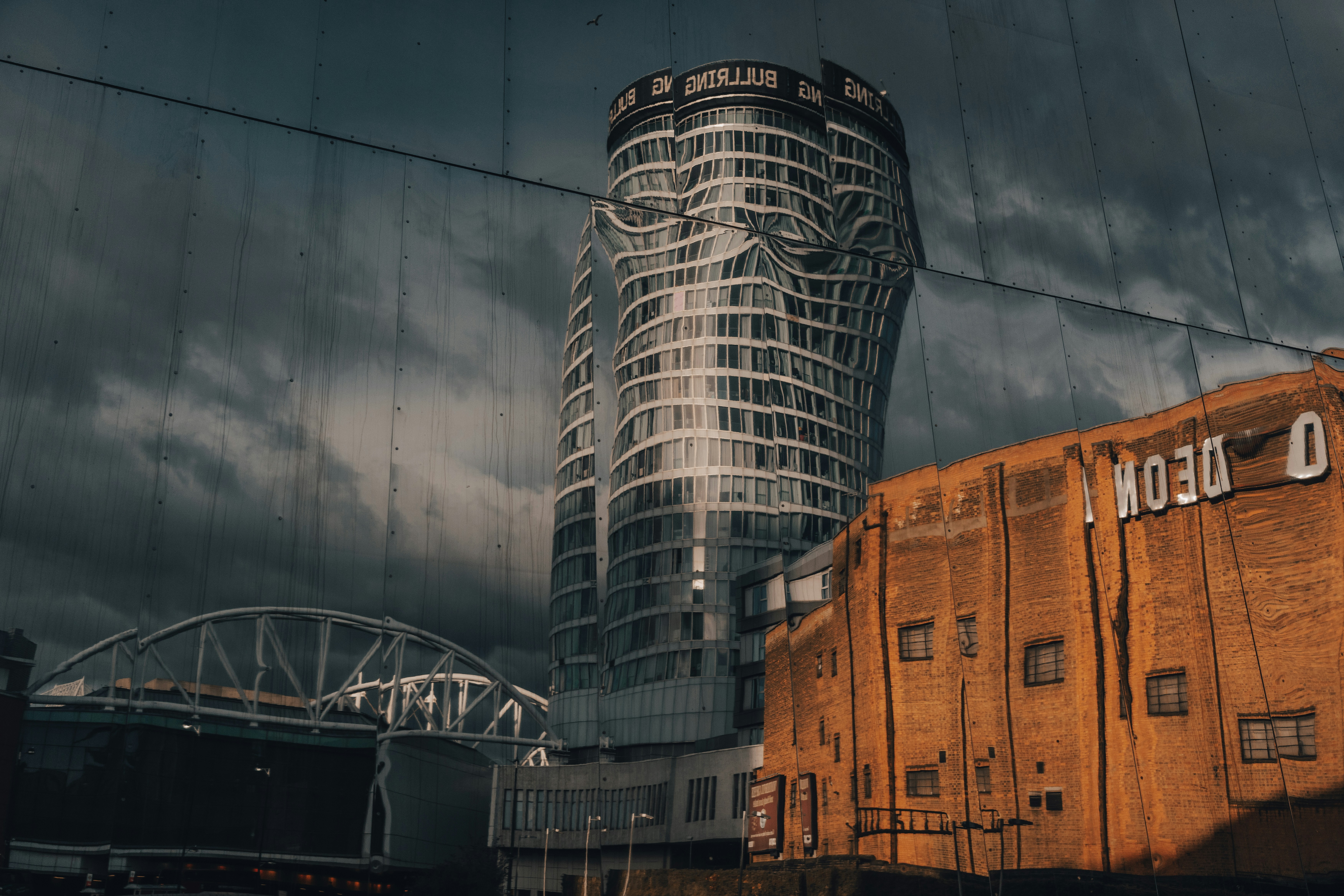 Distorted skyscraper reflection on a glass facade with contrasting textures and colors.