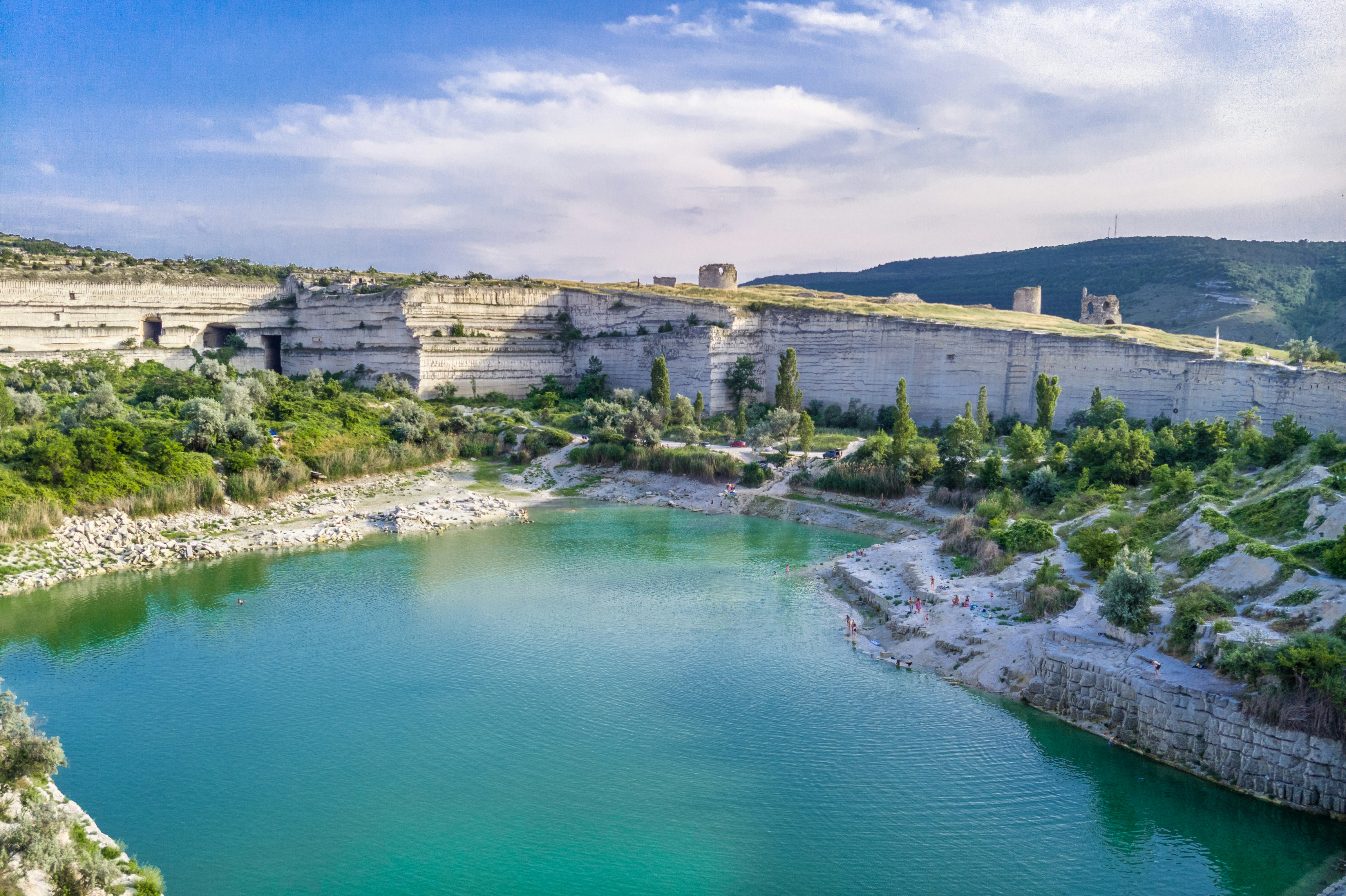 A tranquil turquoise lake surrounded by ancient stone cliffs and lush greenery, evoking a sense of peace and historical significance.