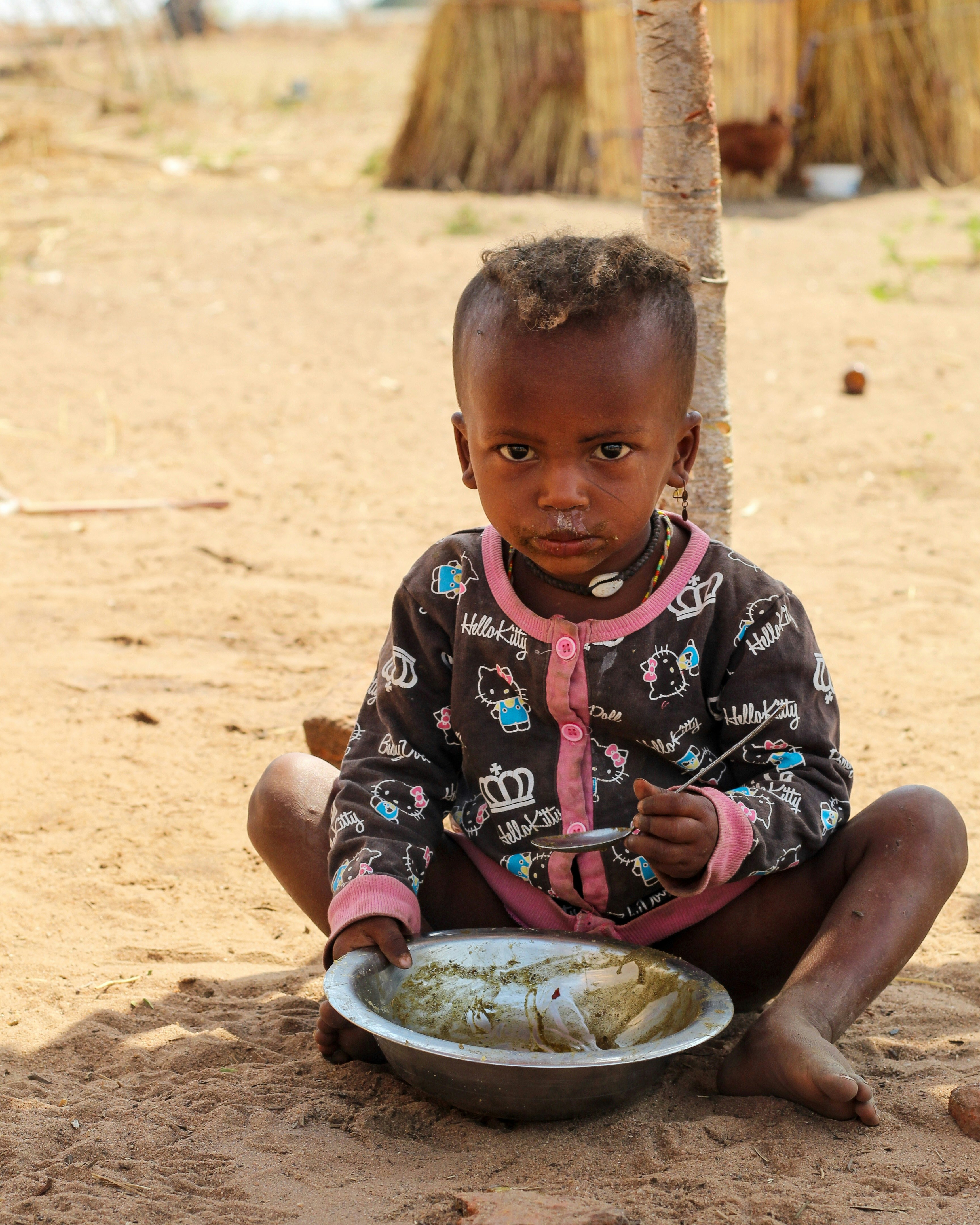 A young child sitting on the ground eating food photo – Free Baby Image ...