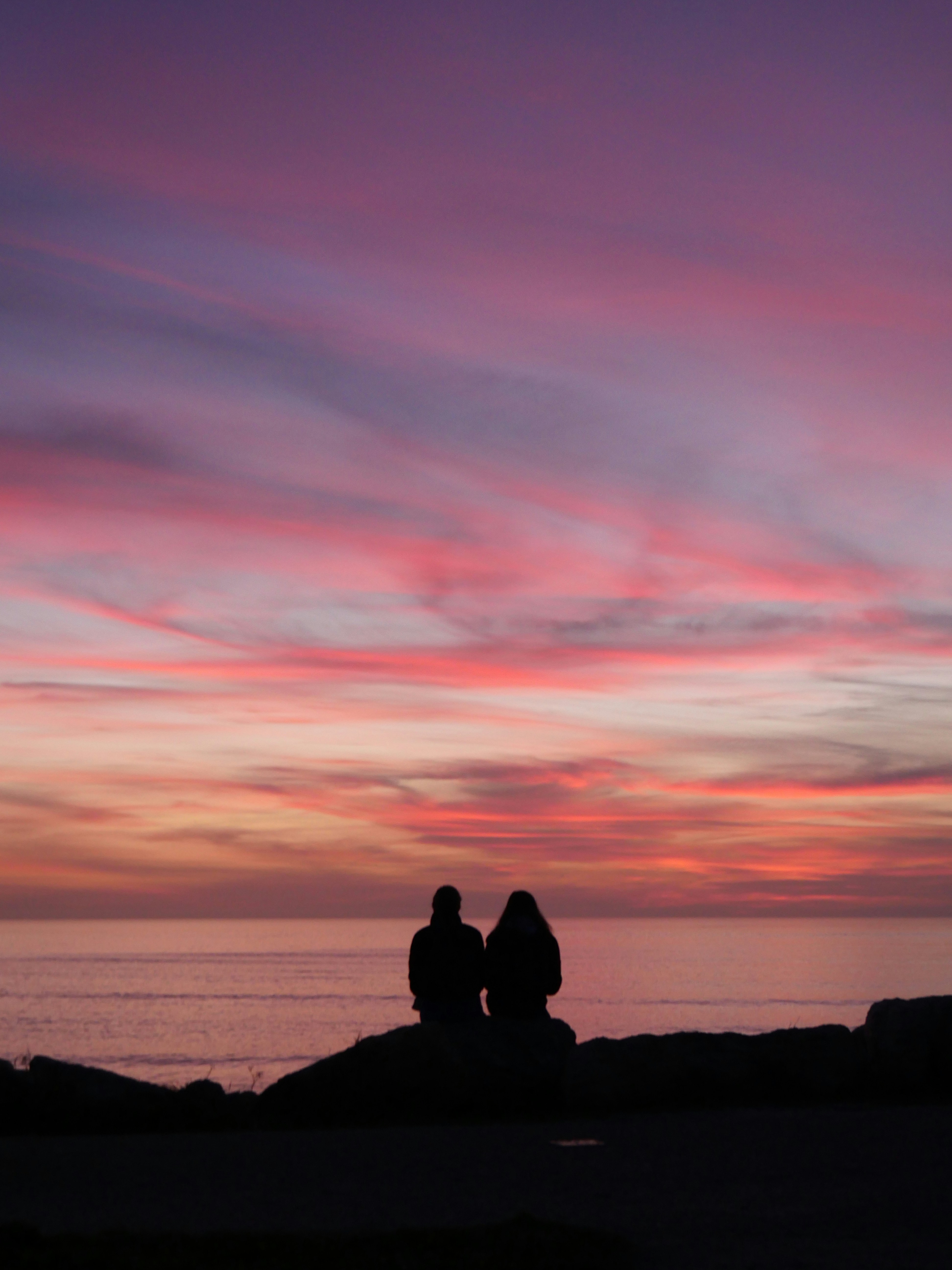 Two people sitting on a rock watching the sunset photo – Free La ...