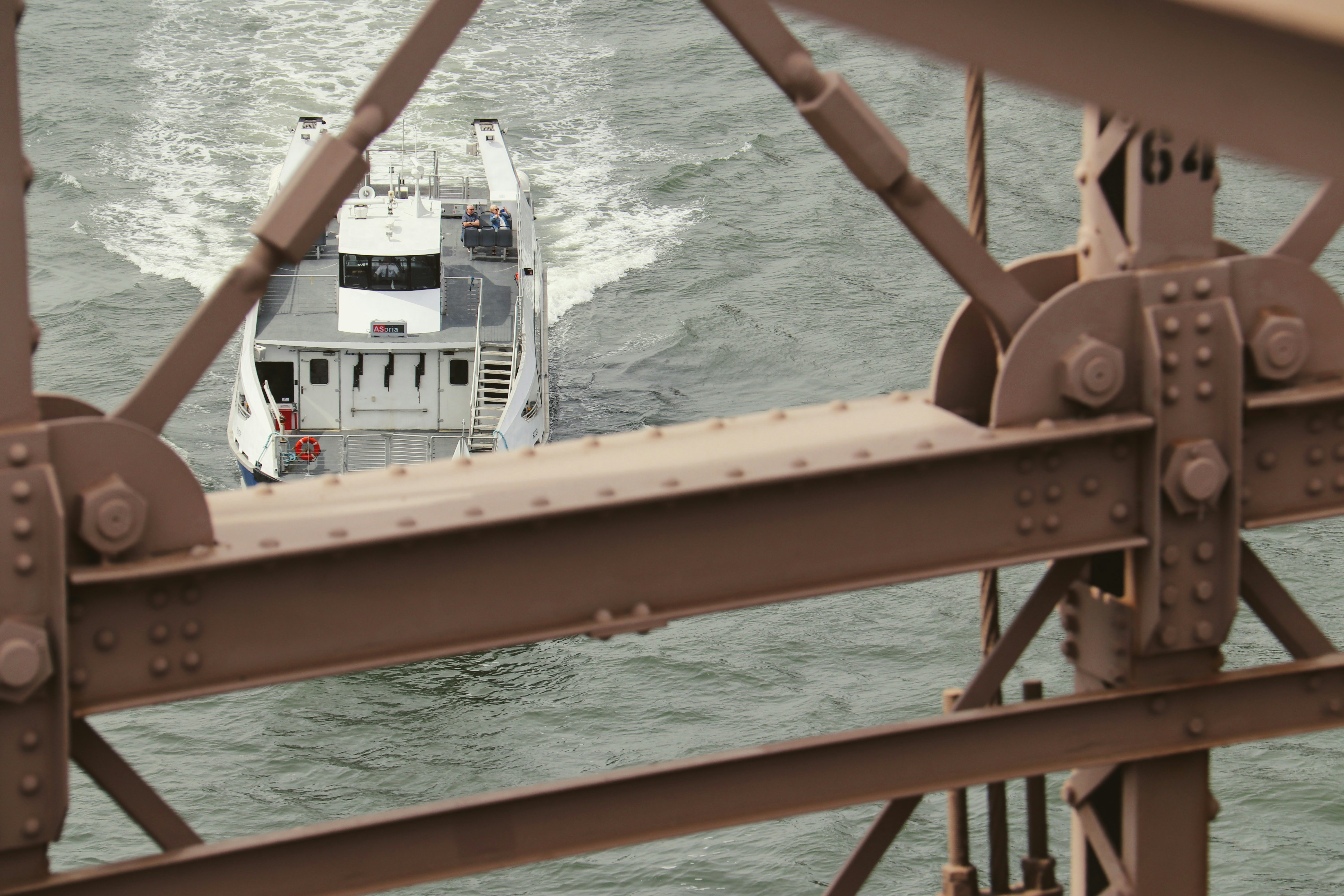 Boat Emerges Through Rusted Truss: a riverboat framed by steel above-water