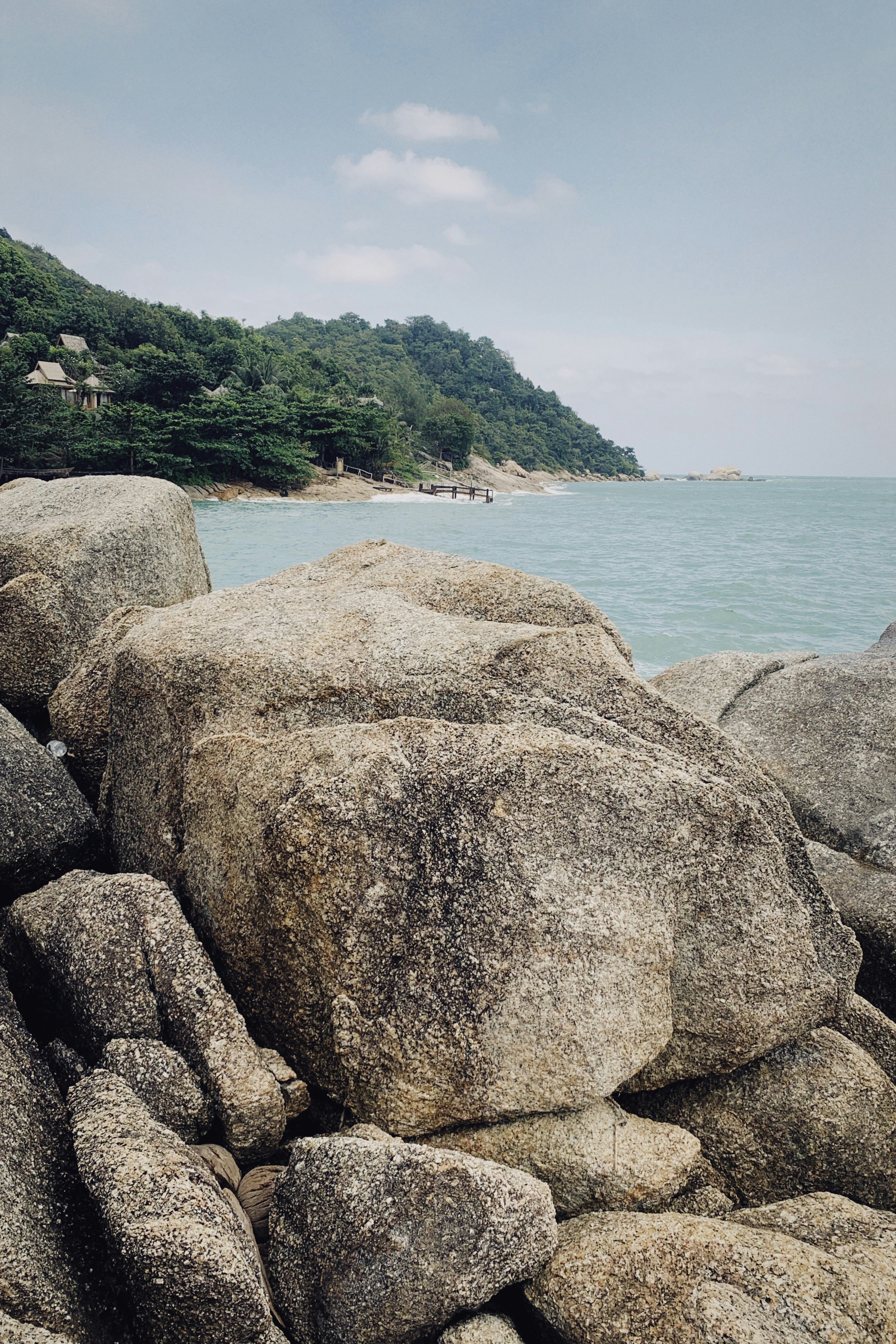 A large rock sitting on top of a beach next to the ocean photo – Free ...