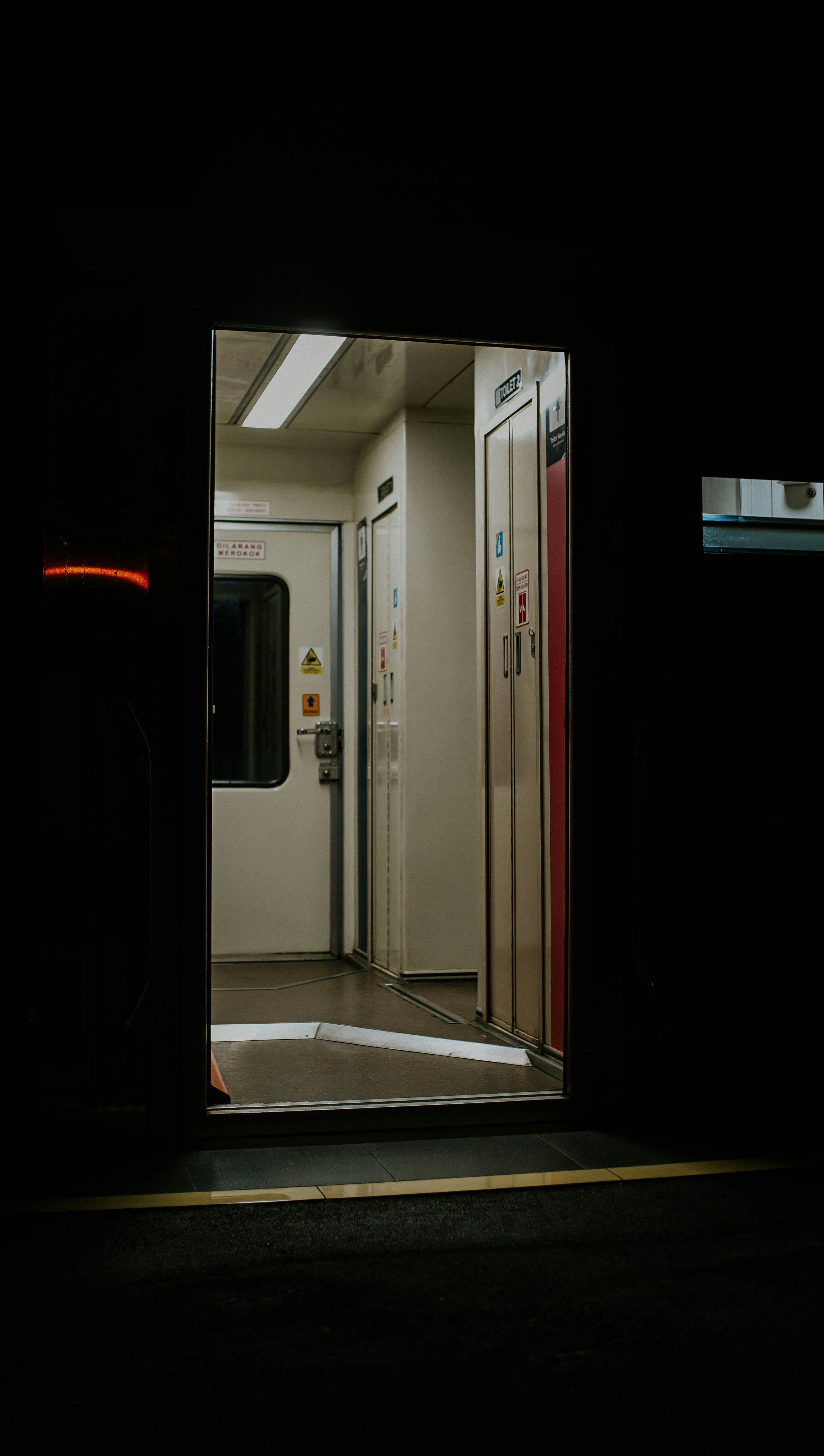 Open train doors revealing a dimly lit interior, inviting exploration and evoking a sense of mystery.