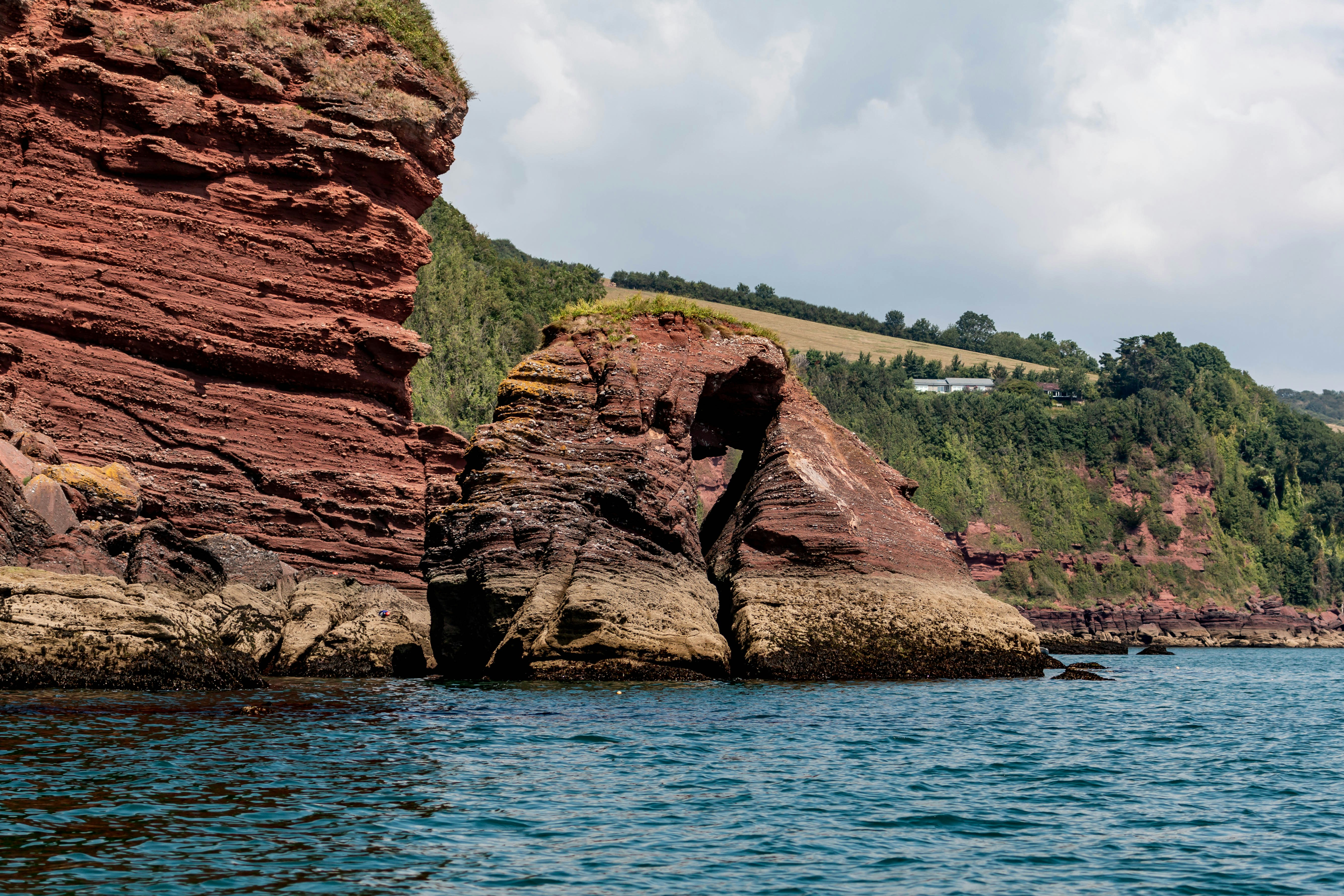A rock formation in the middle of a body of water photo – Free Sea ...
