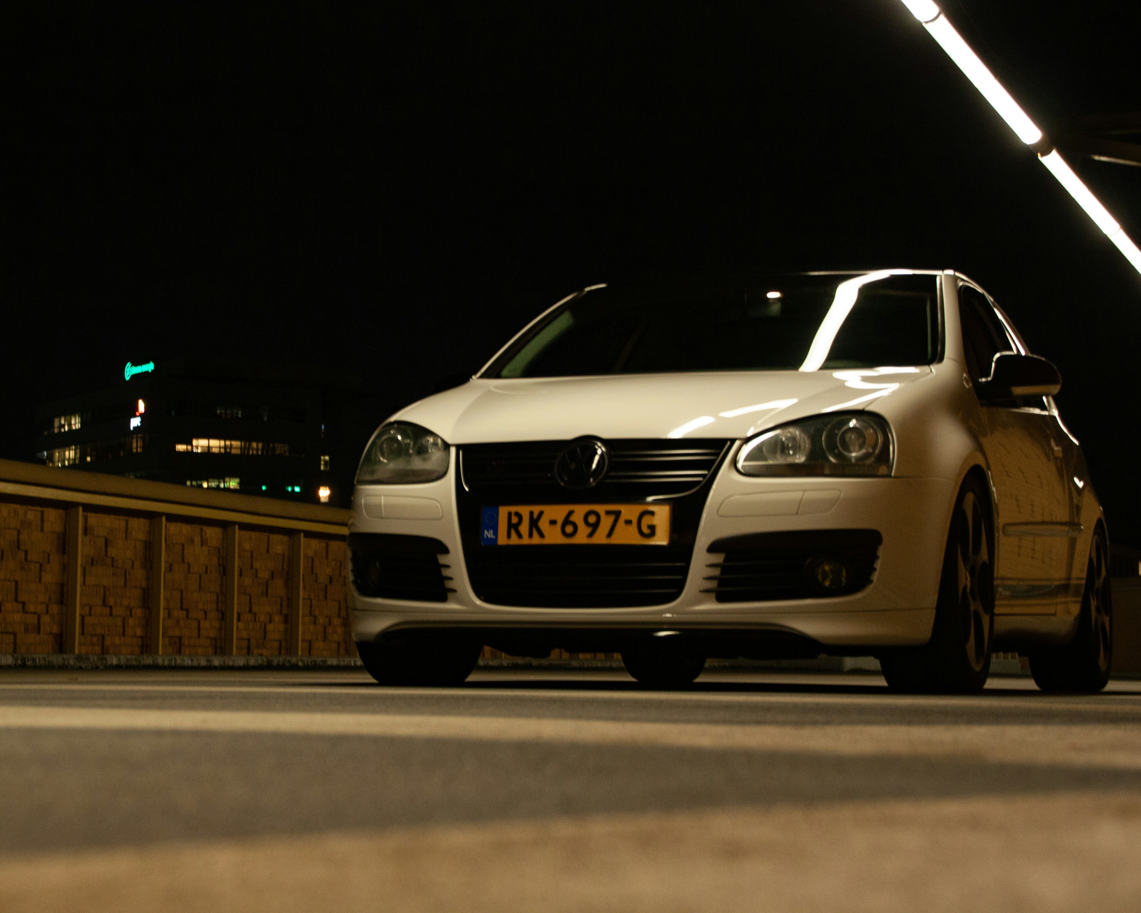 Fluorescent Quiet: White VW Golf Anchored in a Night Parking Garage