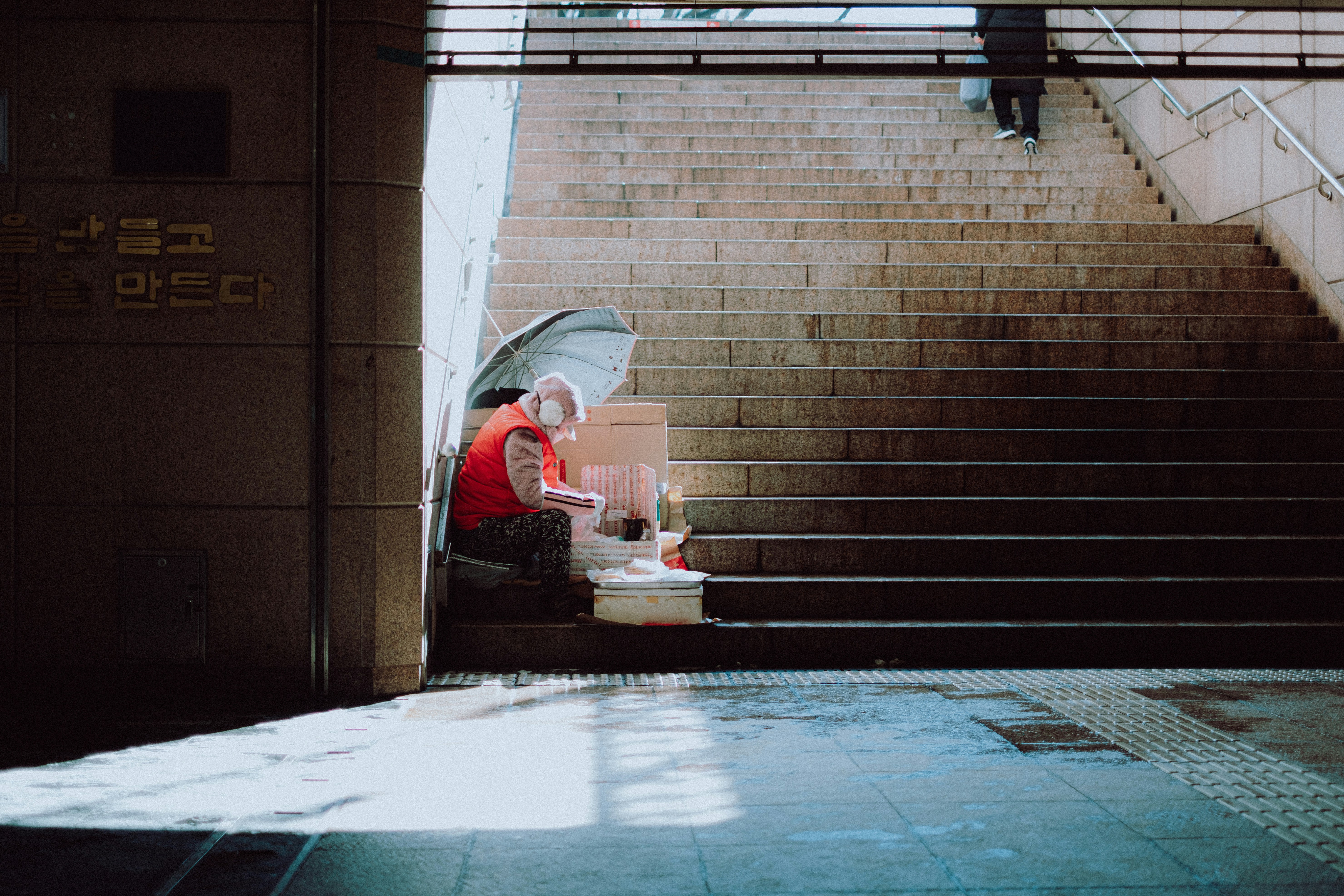 a person sitting on a set of stairs with an umbrella