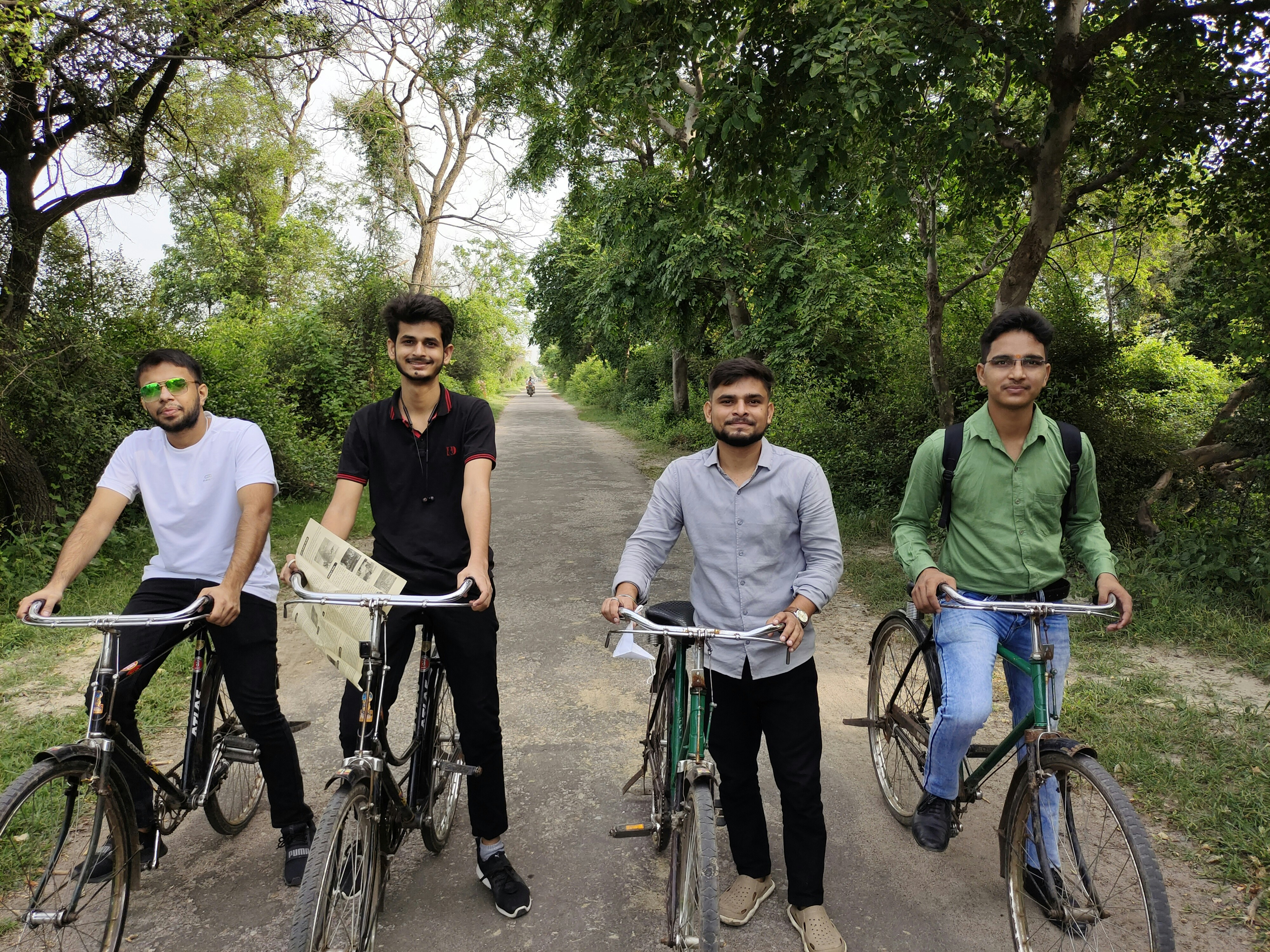 Four individuals with bicycles on a tree-lined path, exuding a sense of camaraderie and adventure.
