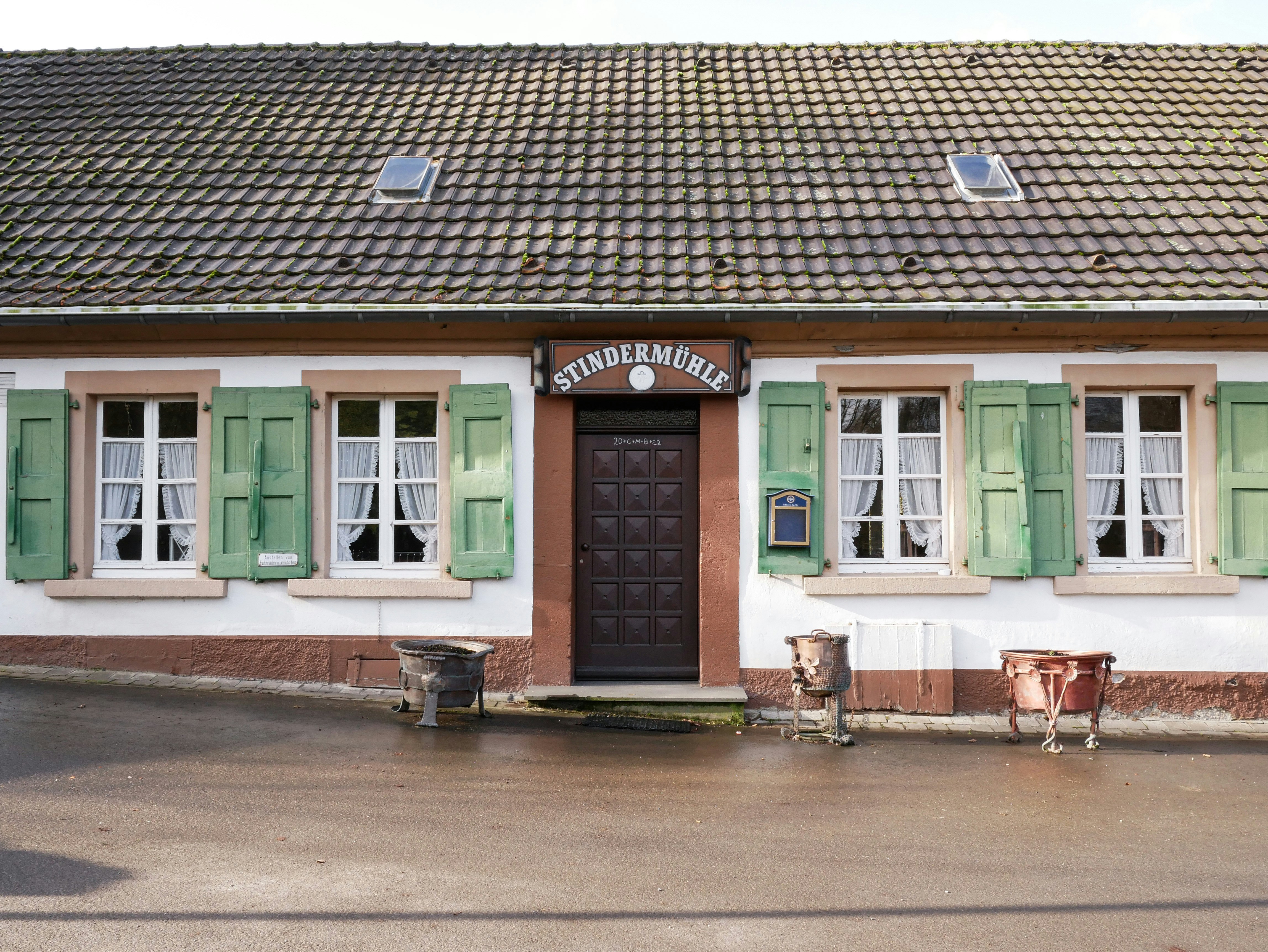 Traditional house with green shutters and brick accents under a tiled roof.