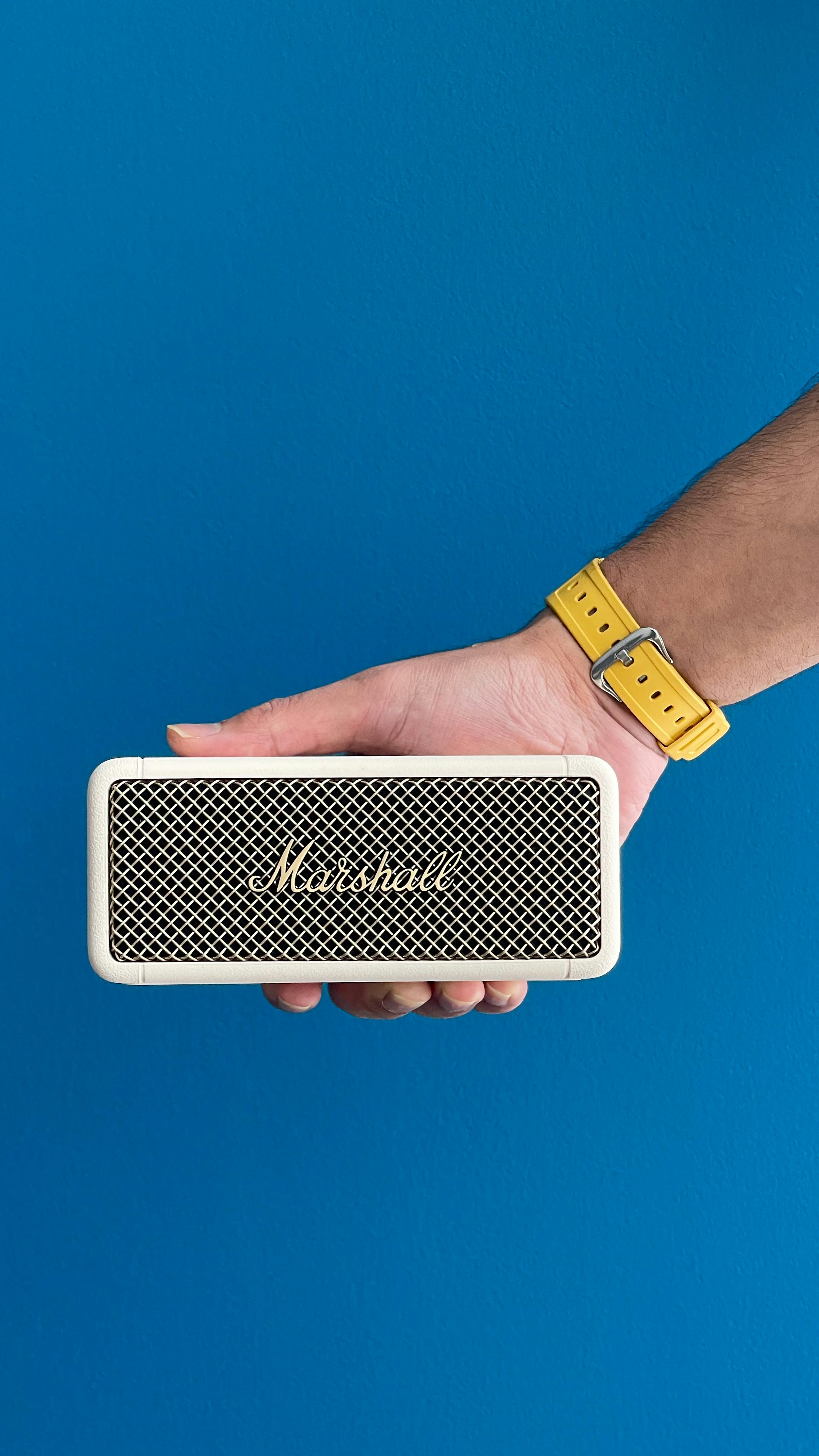 Azure Minimalism: Hand-Held Marshall Speaker on a Solid Blue Wall