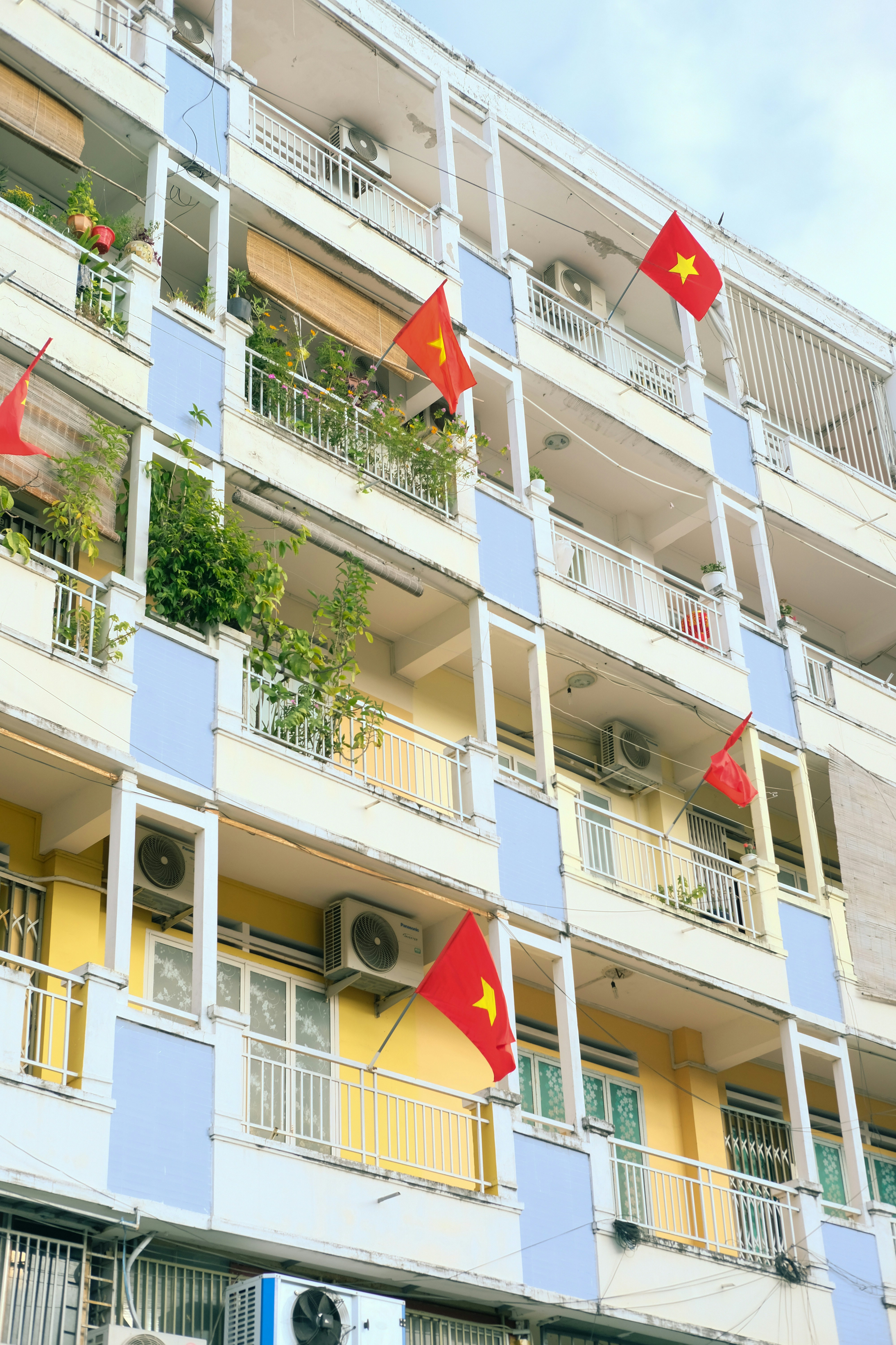 A tall building with balconies and flags on the balconies photo – Free ...