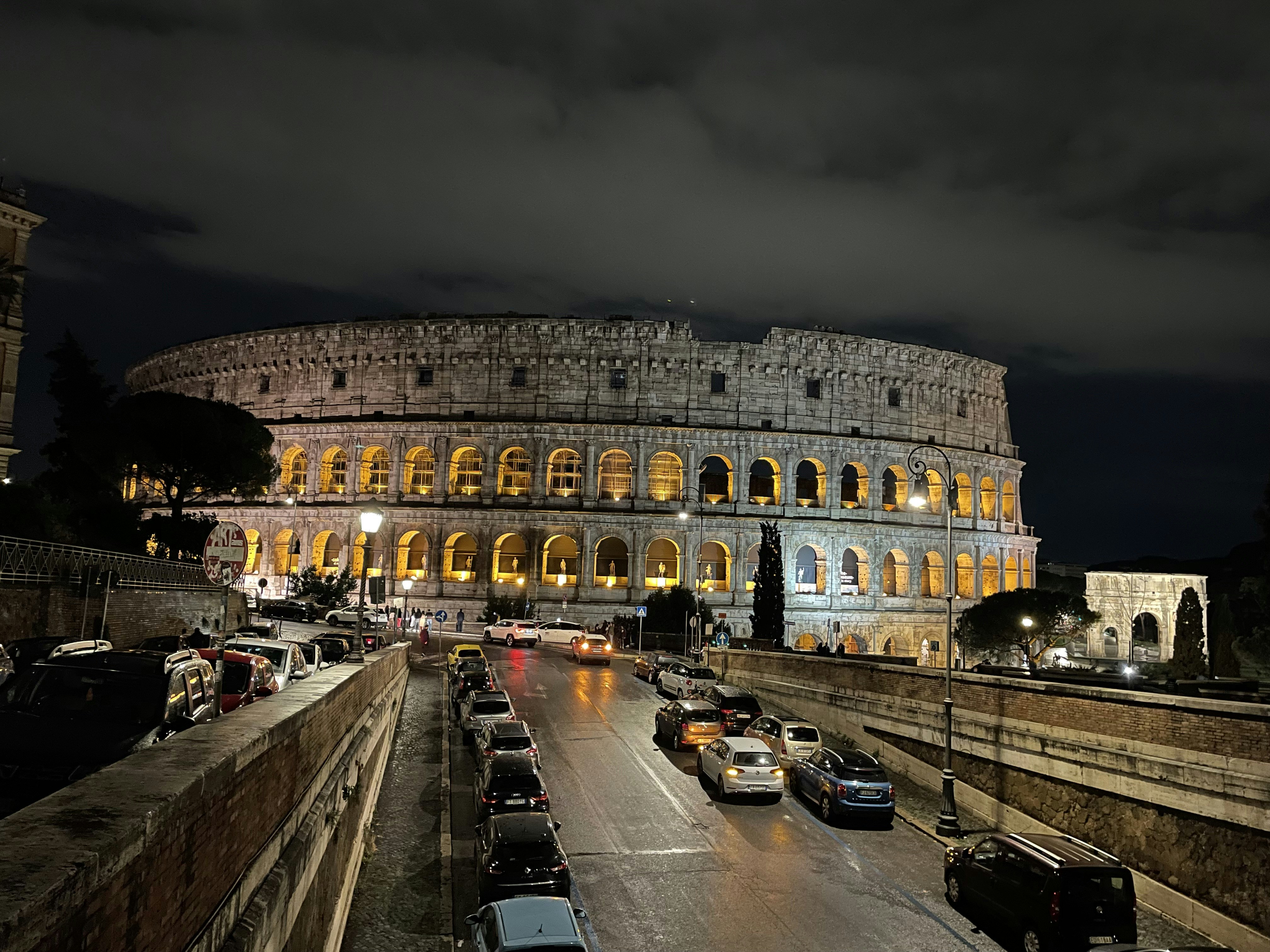 Echoes of Light: Nighttime Colosseum Framed by Car Lights