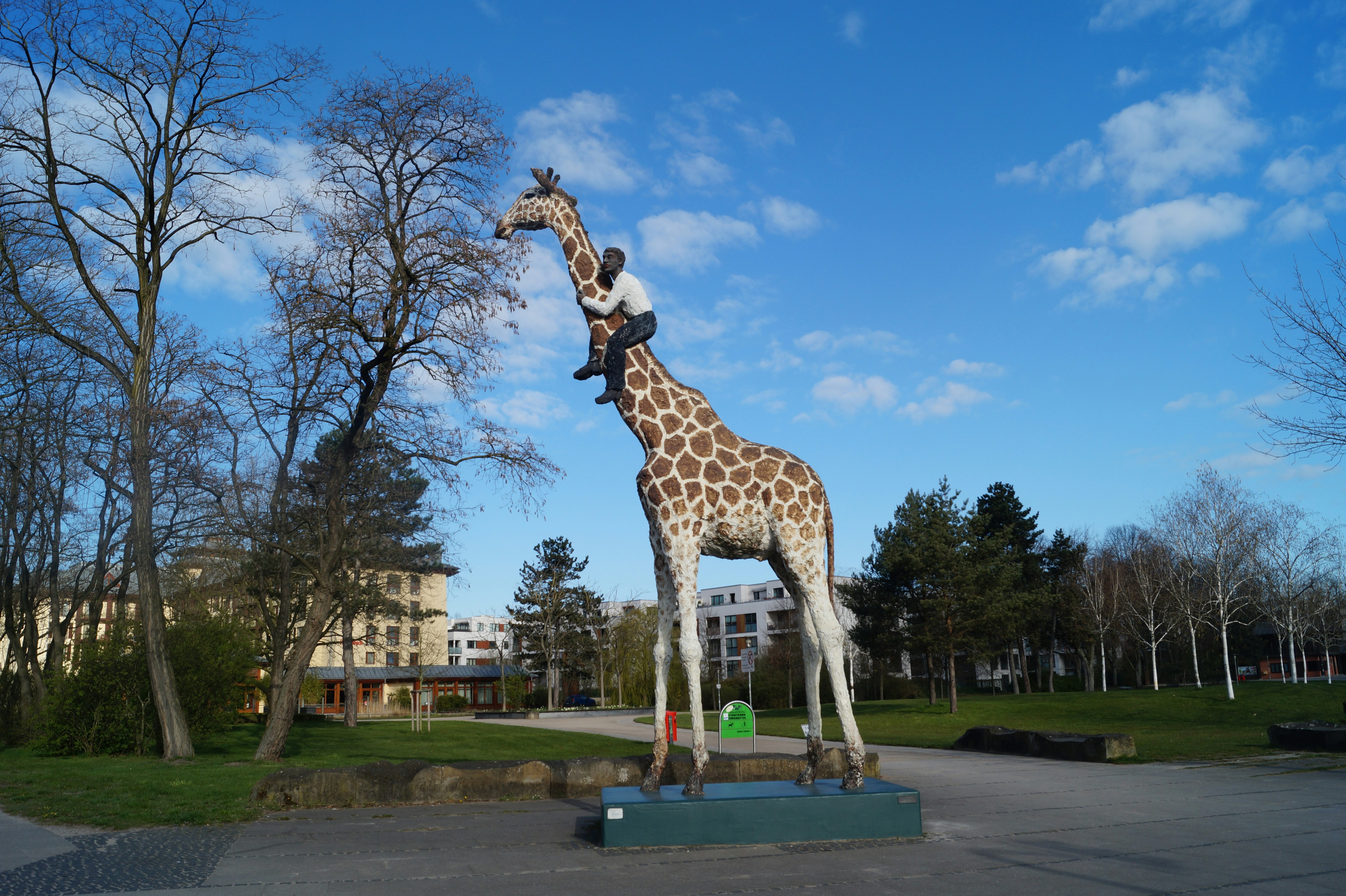 Giraffe on a Pedestal: A Park Sculpture Reaching Toward the Blue