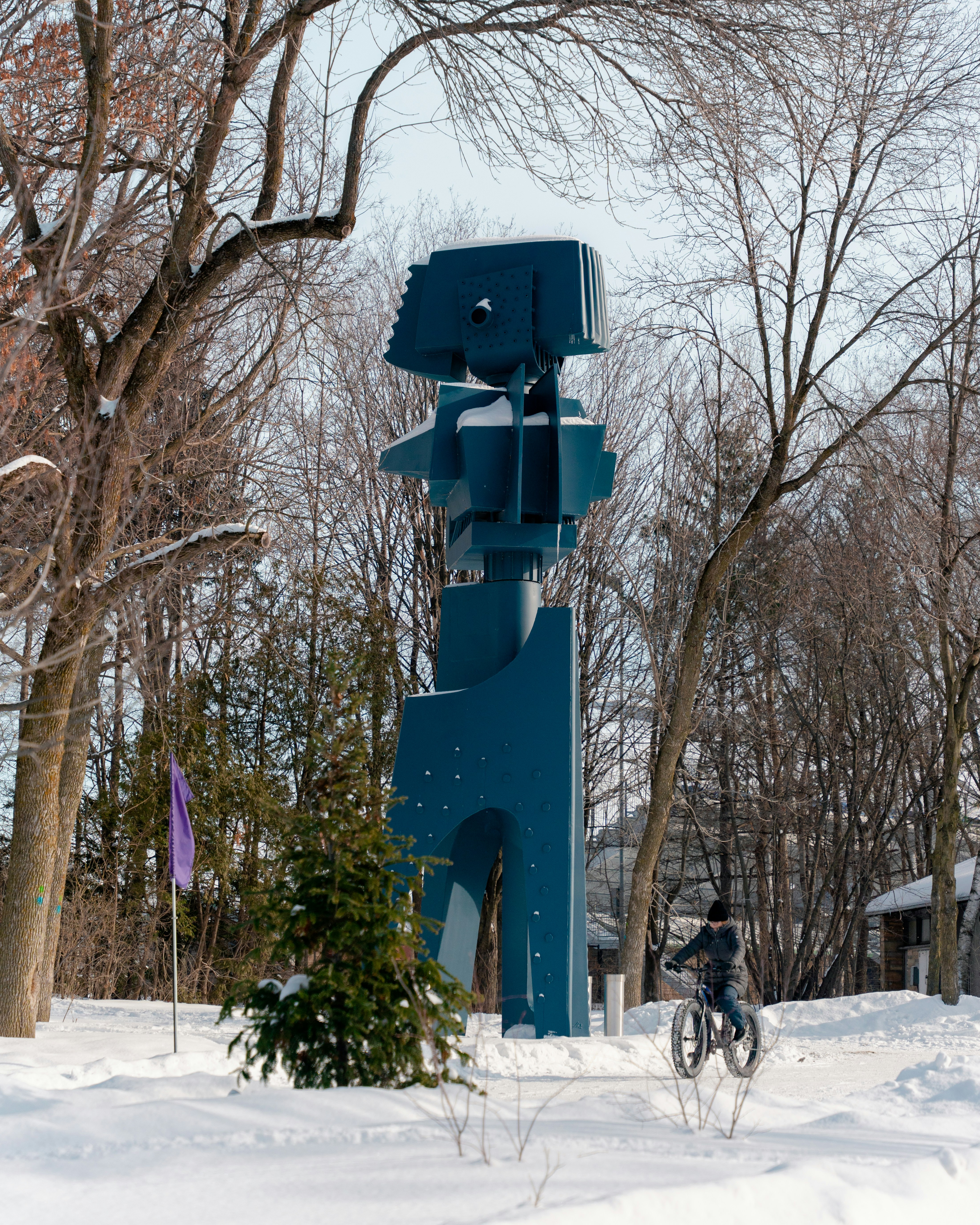a blue sculpture in the middle of a snowy park
