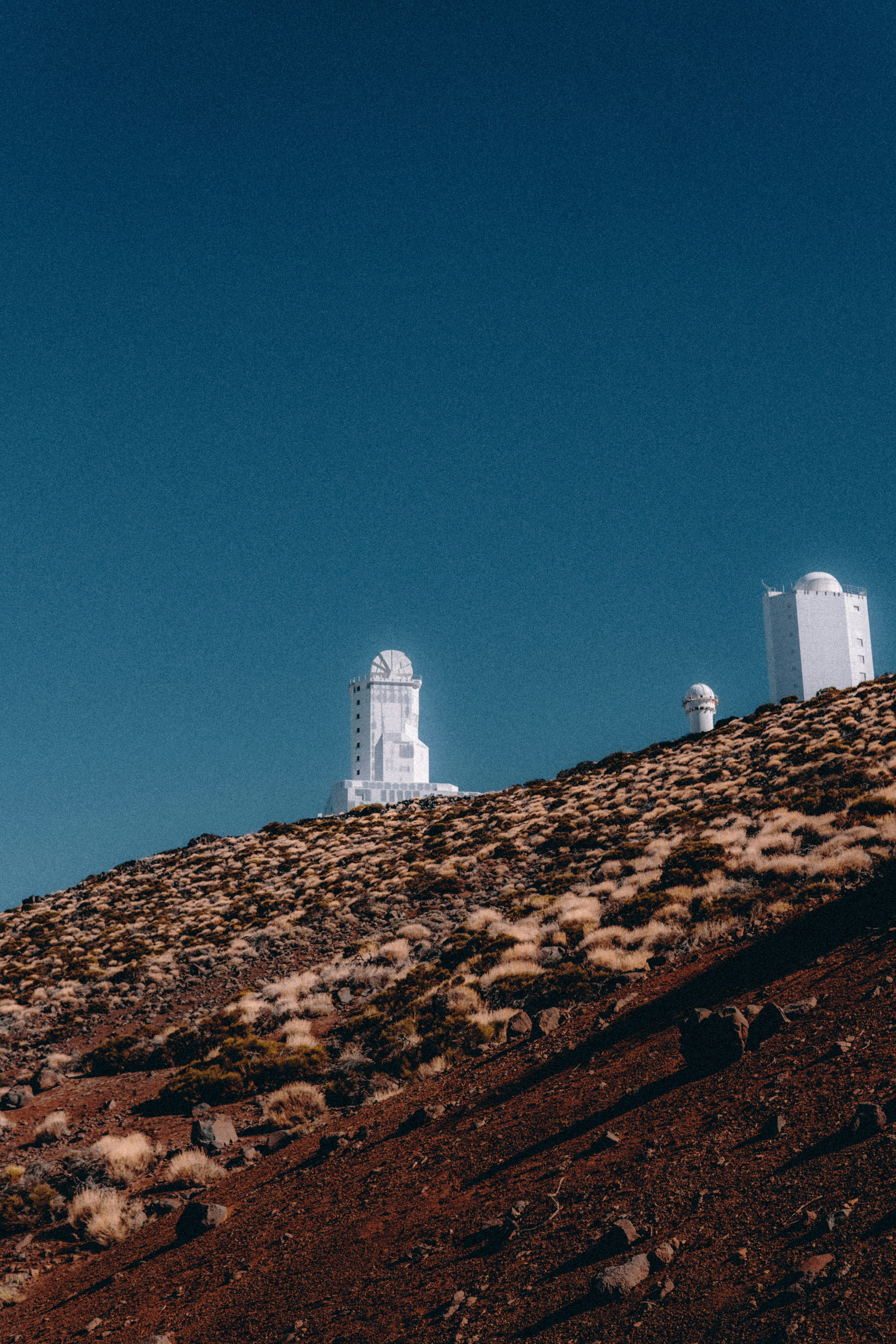 White Domes Guarding a Red Desert Slope Under a Cerulean Sky