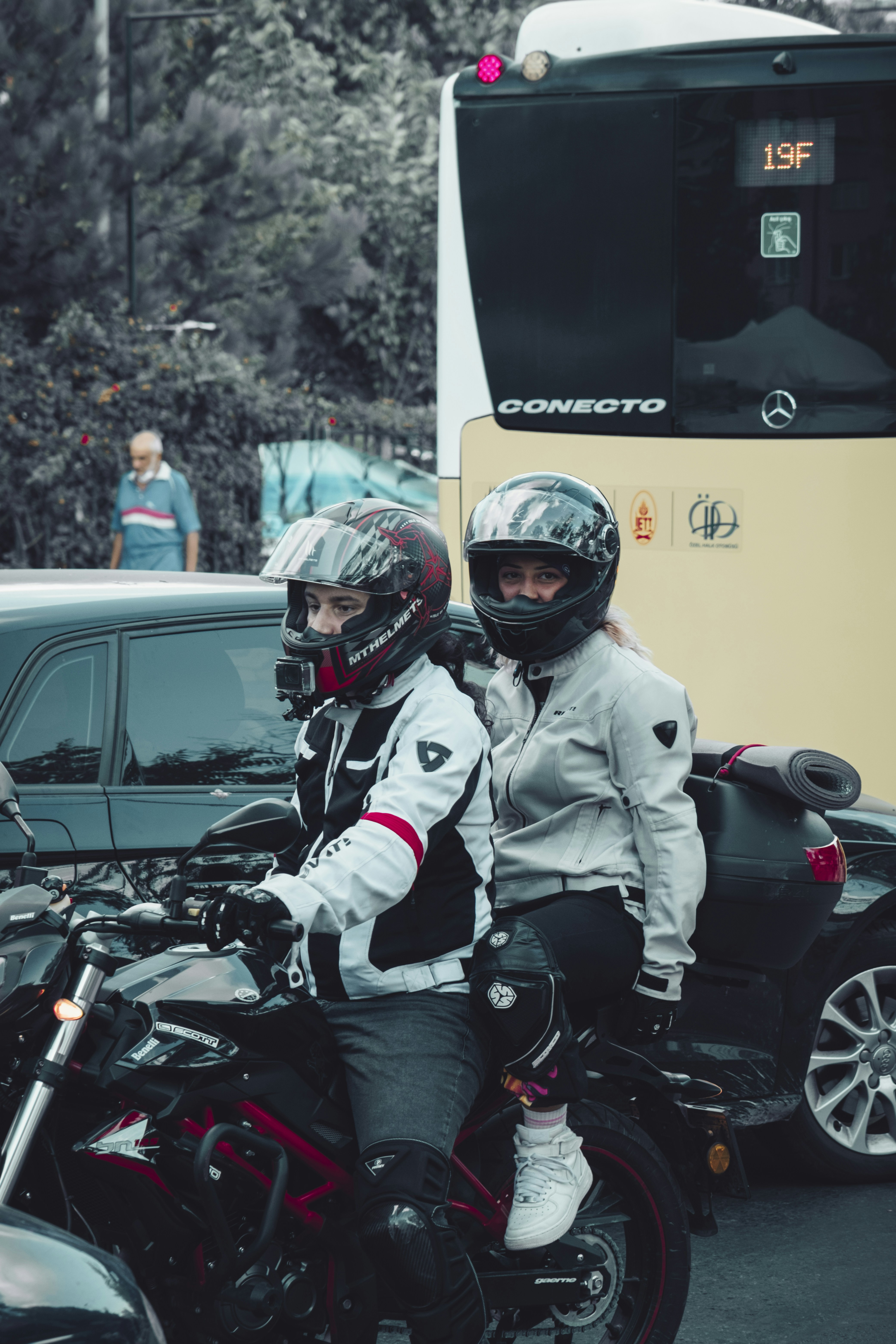 Urban Duo in Motion: Two Riders on a StreetBike Against a Yellow Bus Backdrop