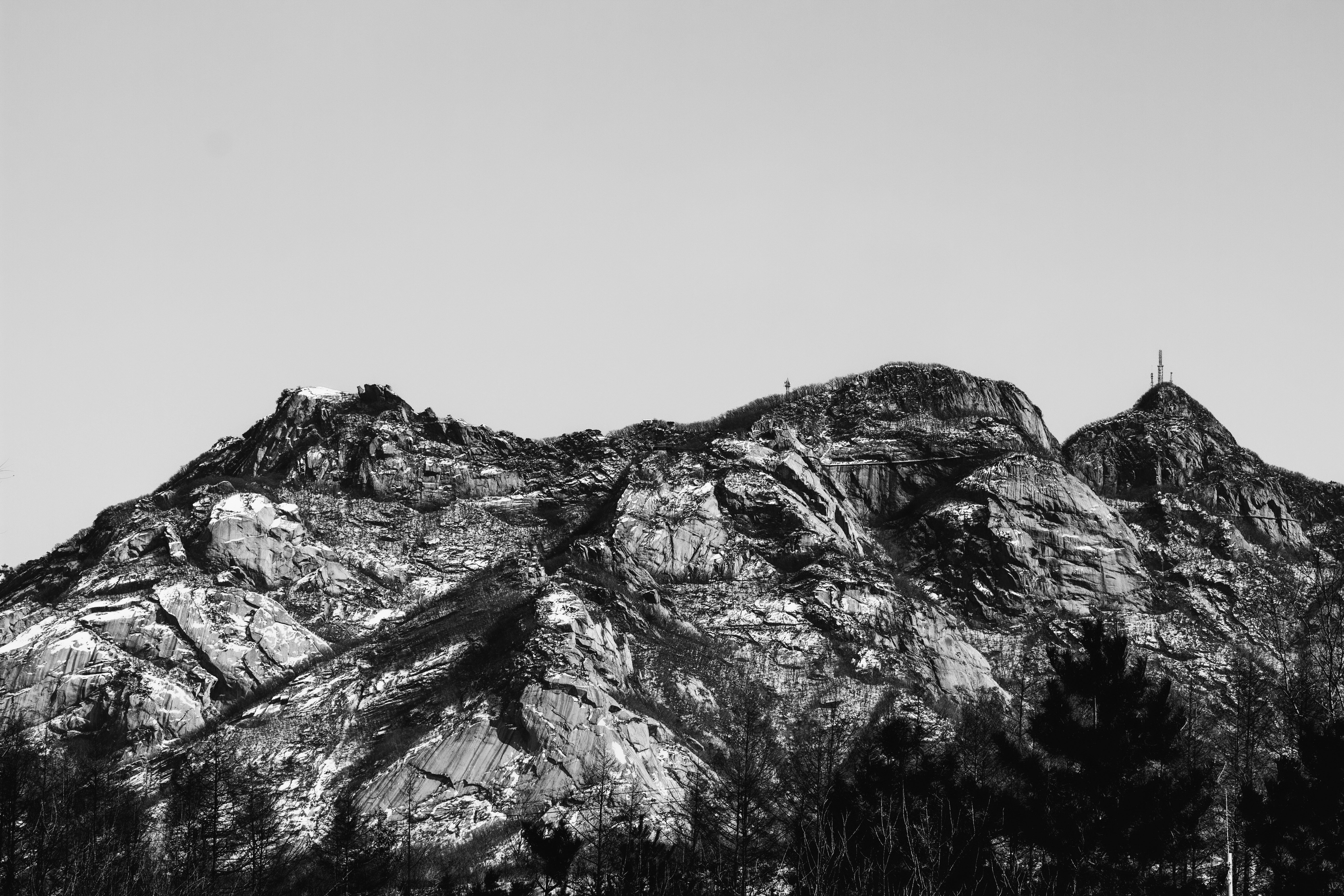 Black and white photograph of rugged mountain range under a clear sky.