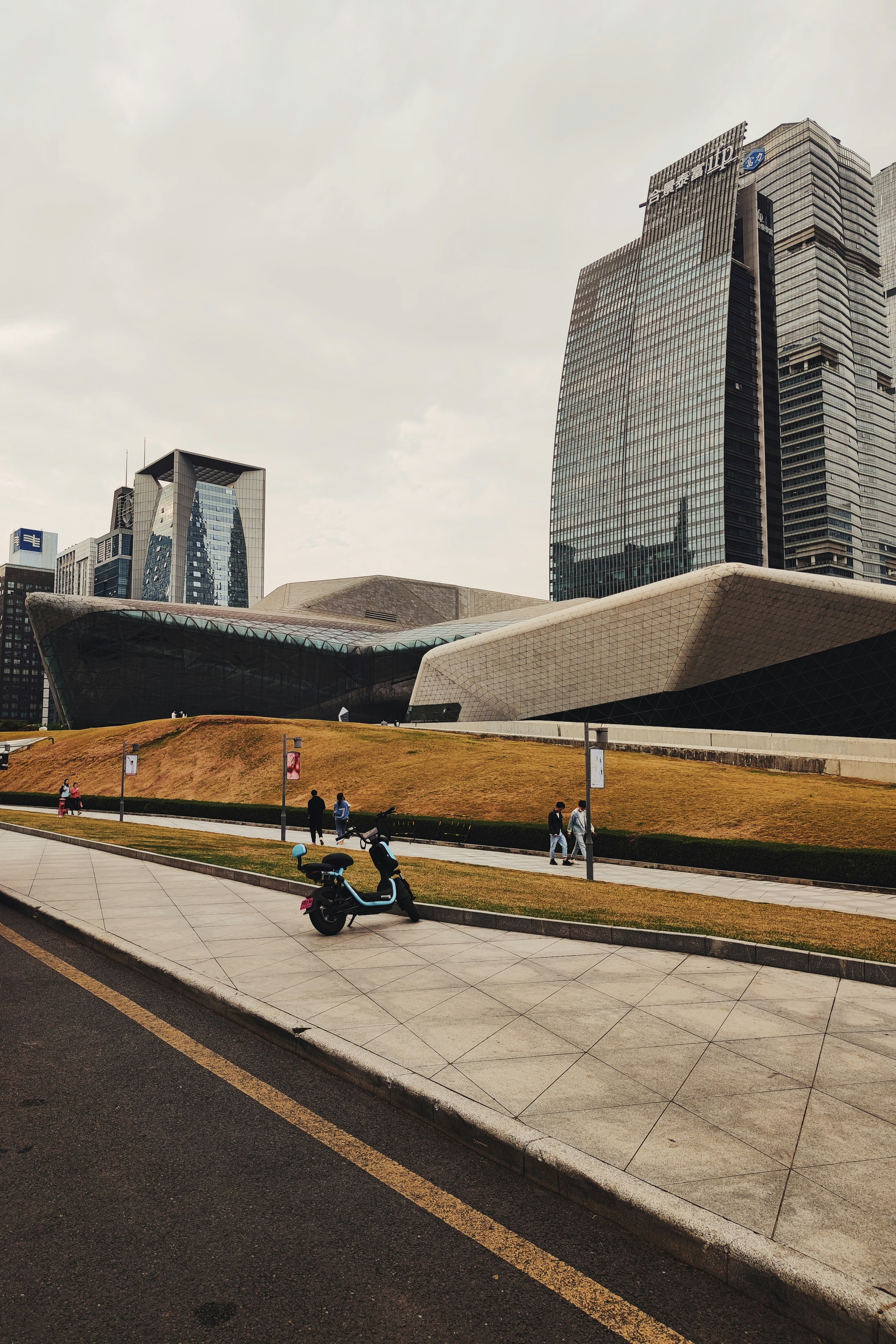 Modern architectural structures juxtaposed with landscaped hills and pedestrians, showcasing the integration of urban design and natural elements.