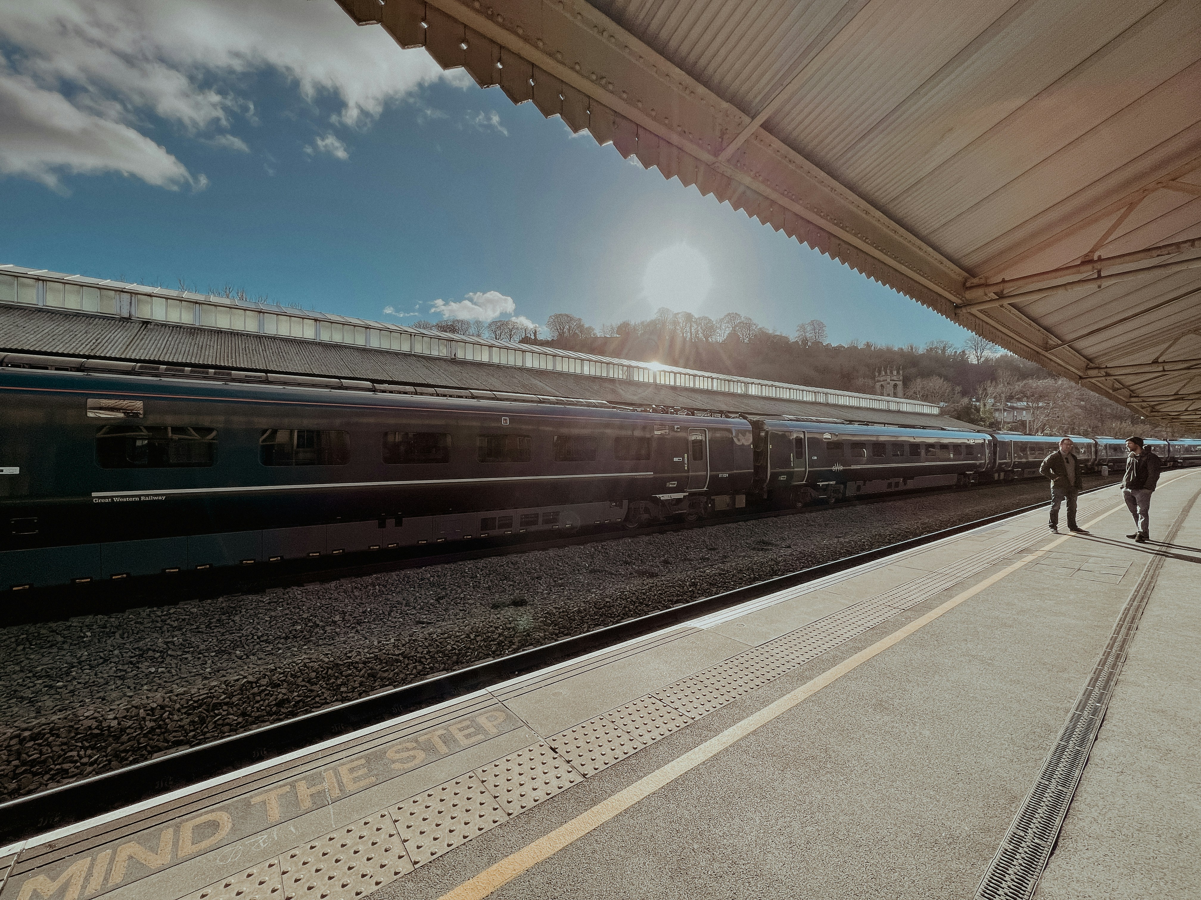 Sunlit Rails: A Long Passenger Train Quietly Spans the Platform
