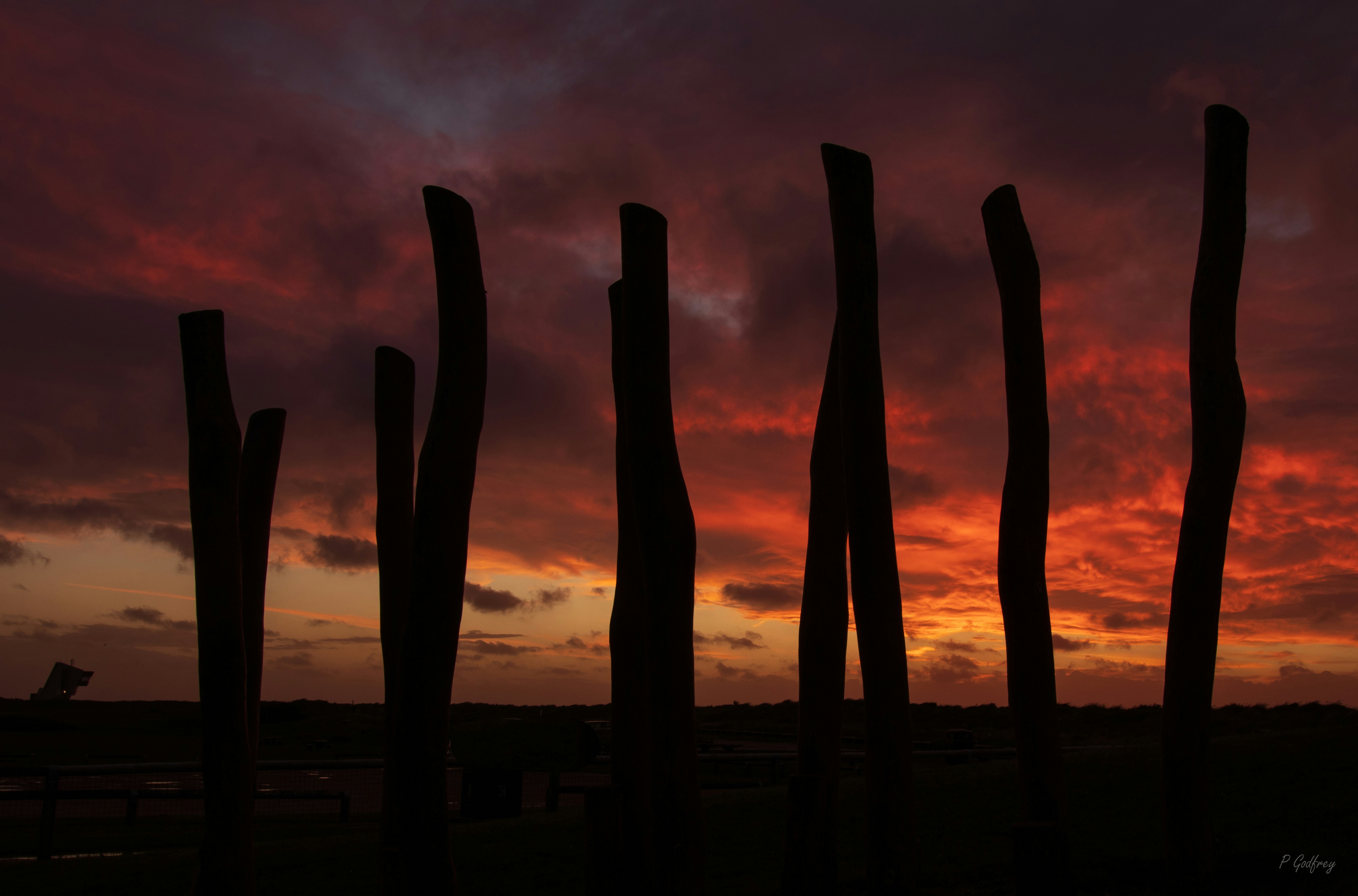 Silhouetted posts at a fiery horizon