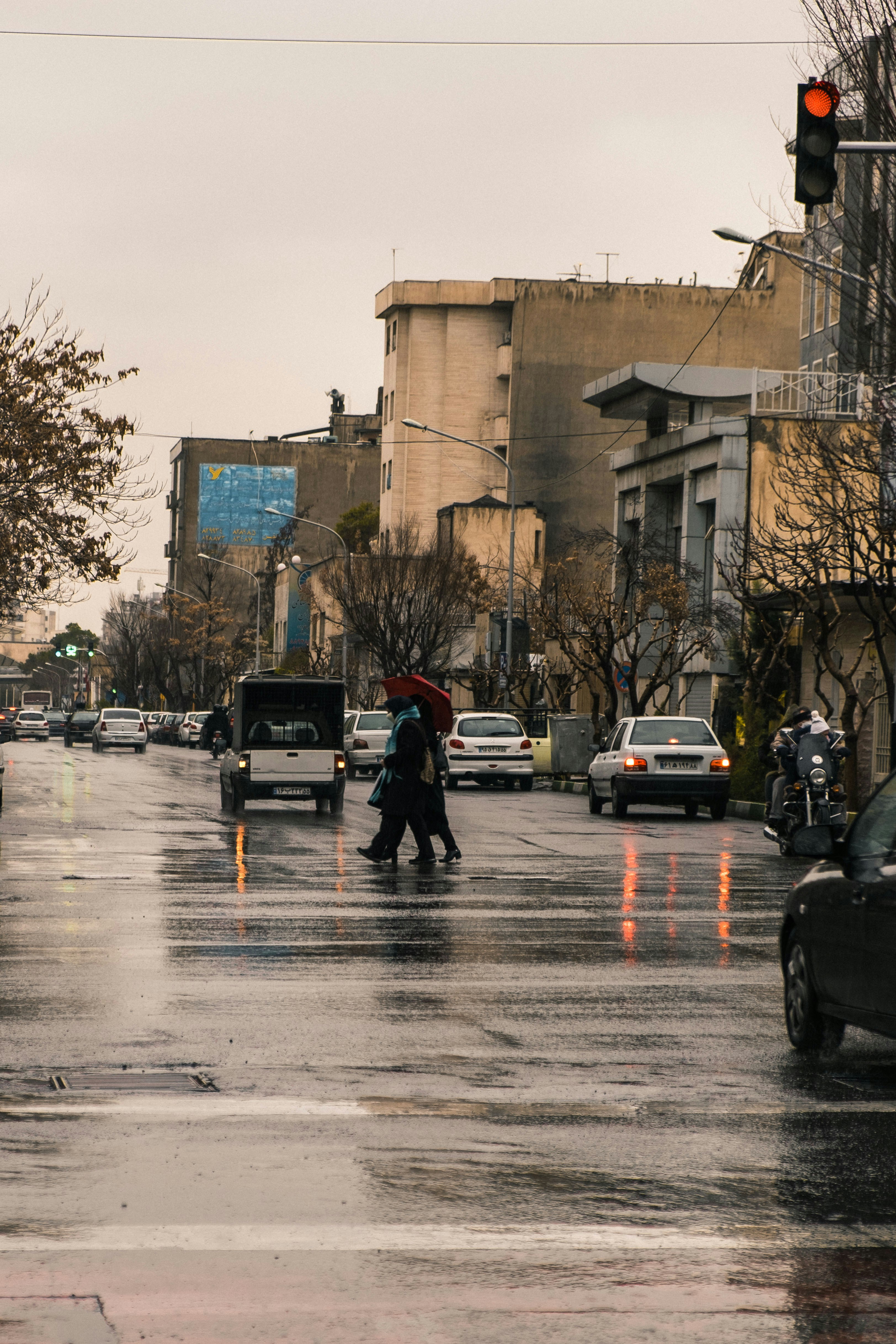 a person walking across a wet street holding an umbrella
