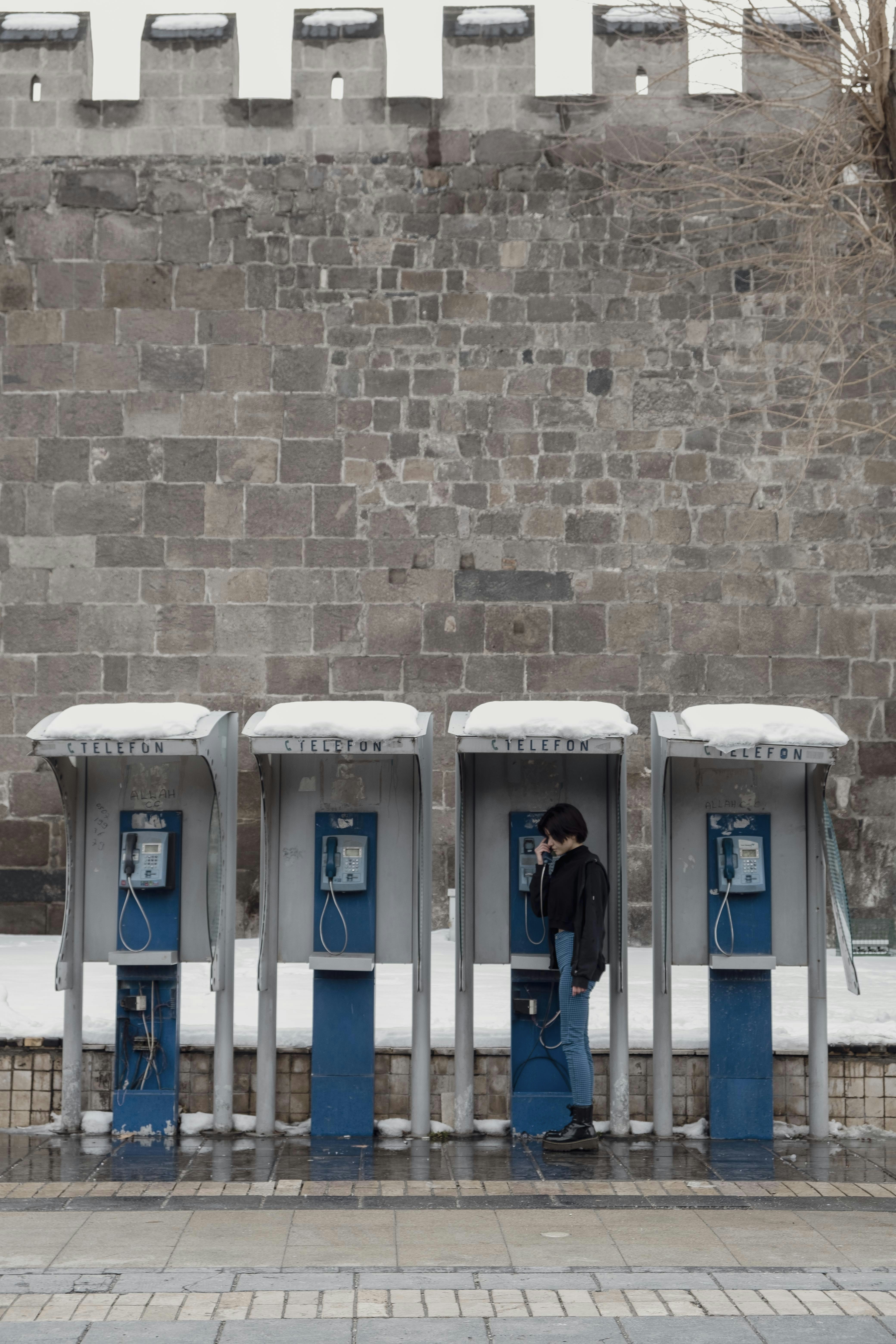 A man standing in front of a row of phone booths photo – Free Human ...