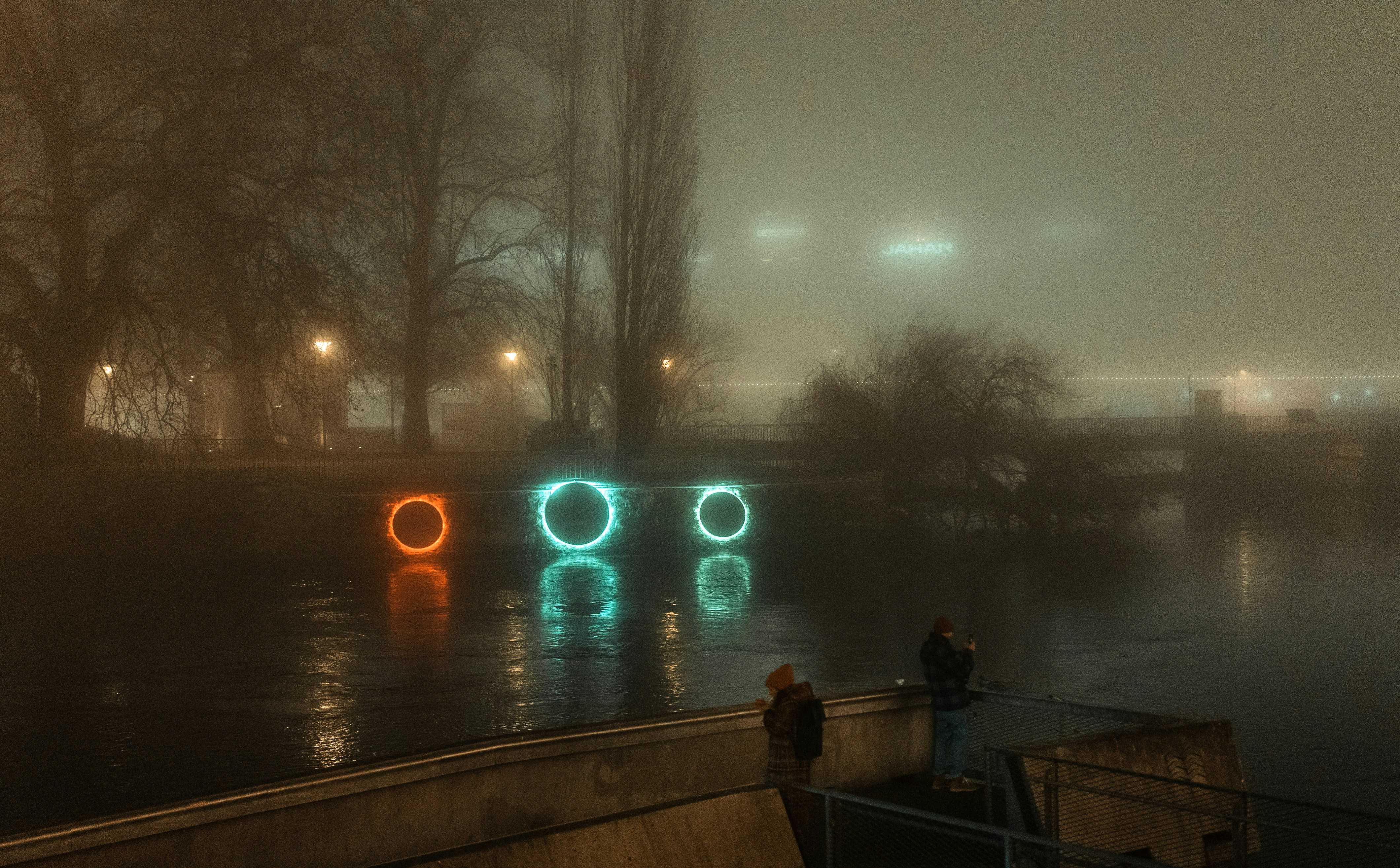 a couple of people standing next to a river