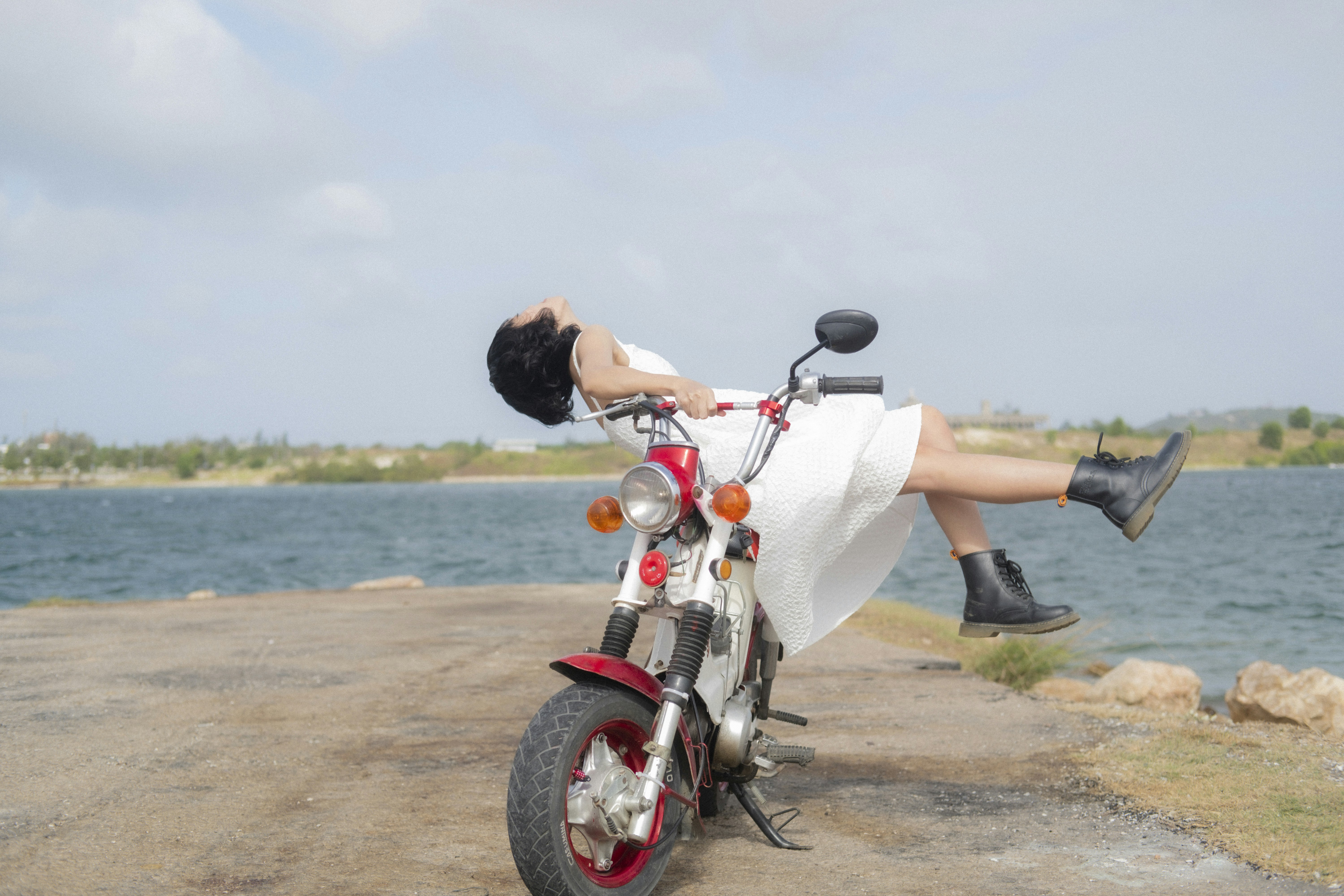 A person laying on a motorcycle near a body of water photo – Free ...