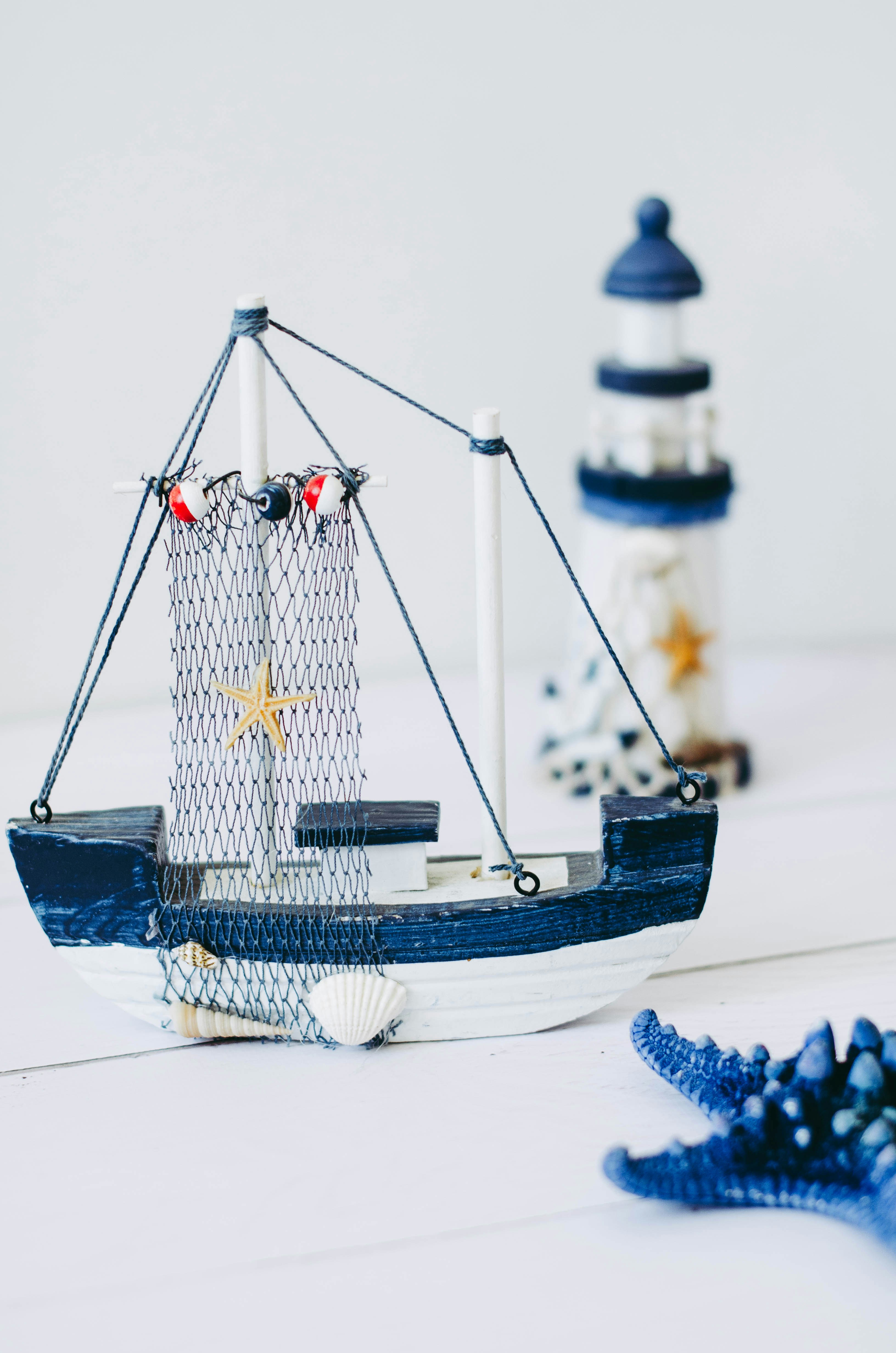 Blue Voyage in Miniature: A Sailboat with Netting and a Distant Lighthouse