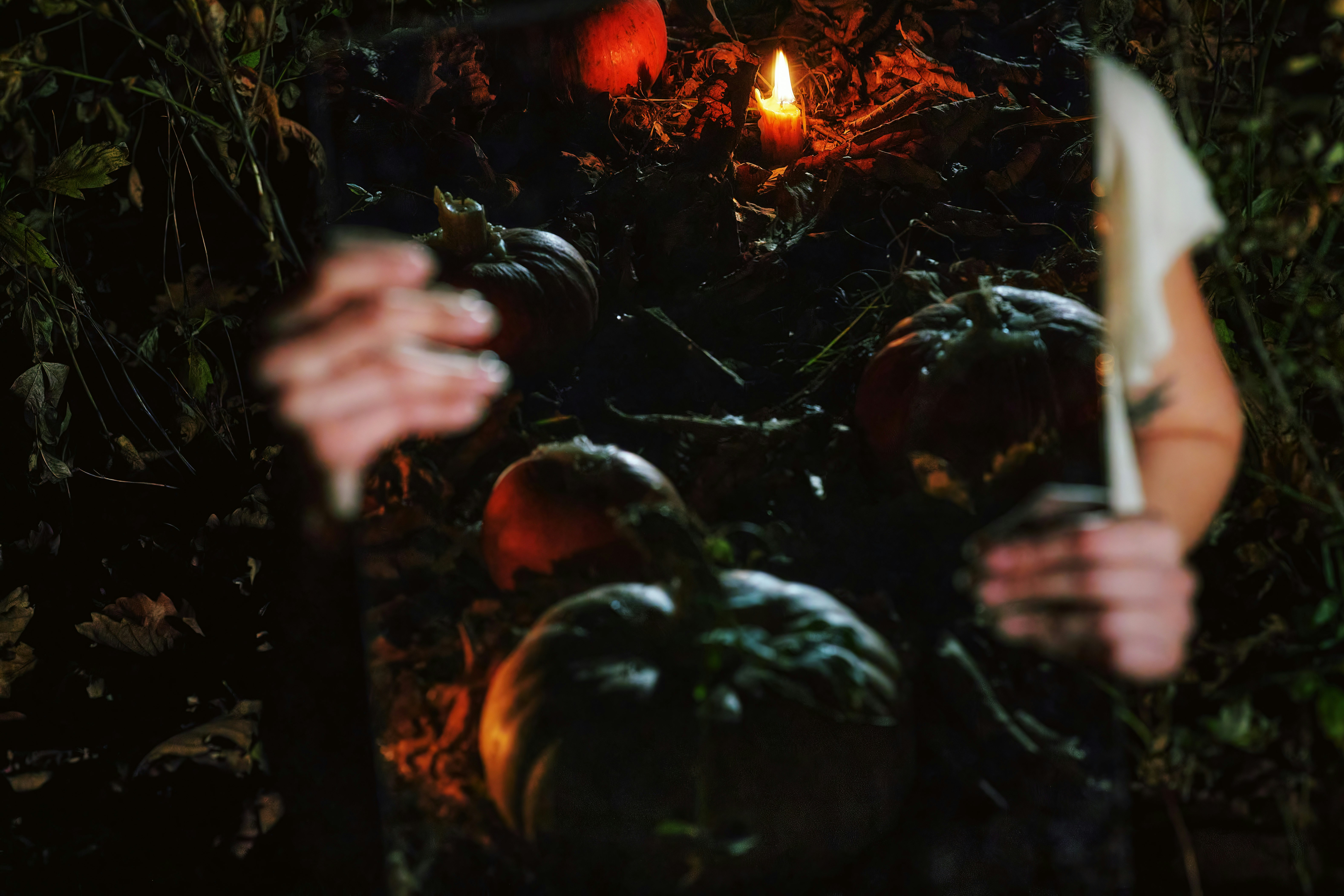 Pumpkins and a candle's glow reflected in a mirror against a blurred, dimly lit background.