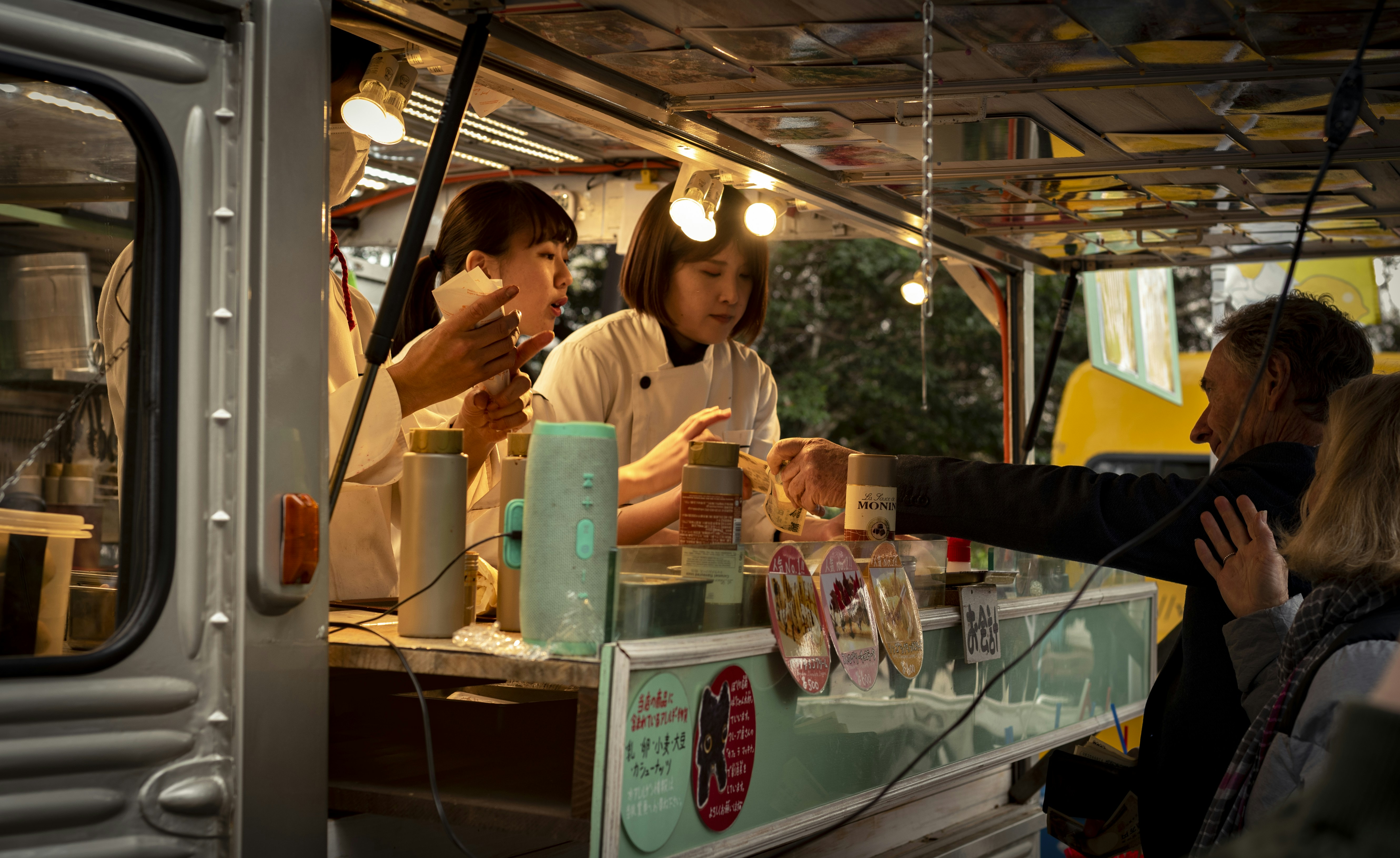Food truck scene with vendors serving customers under warm lights, showcasing an interactive culinary experience.