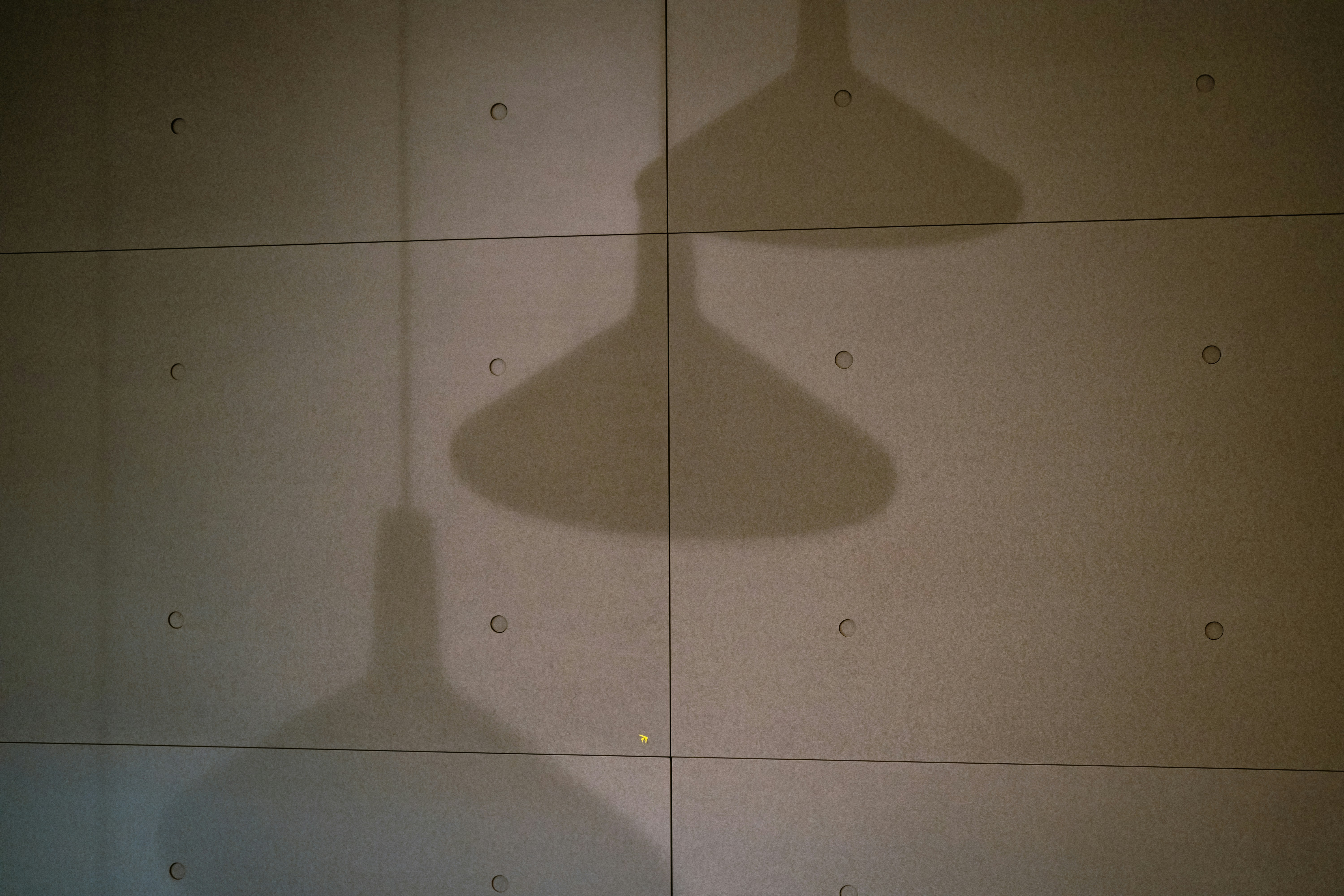 Hanger Shadow in Quiet Geometry on a Panel Wall