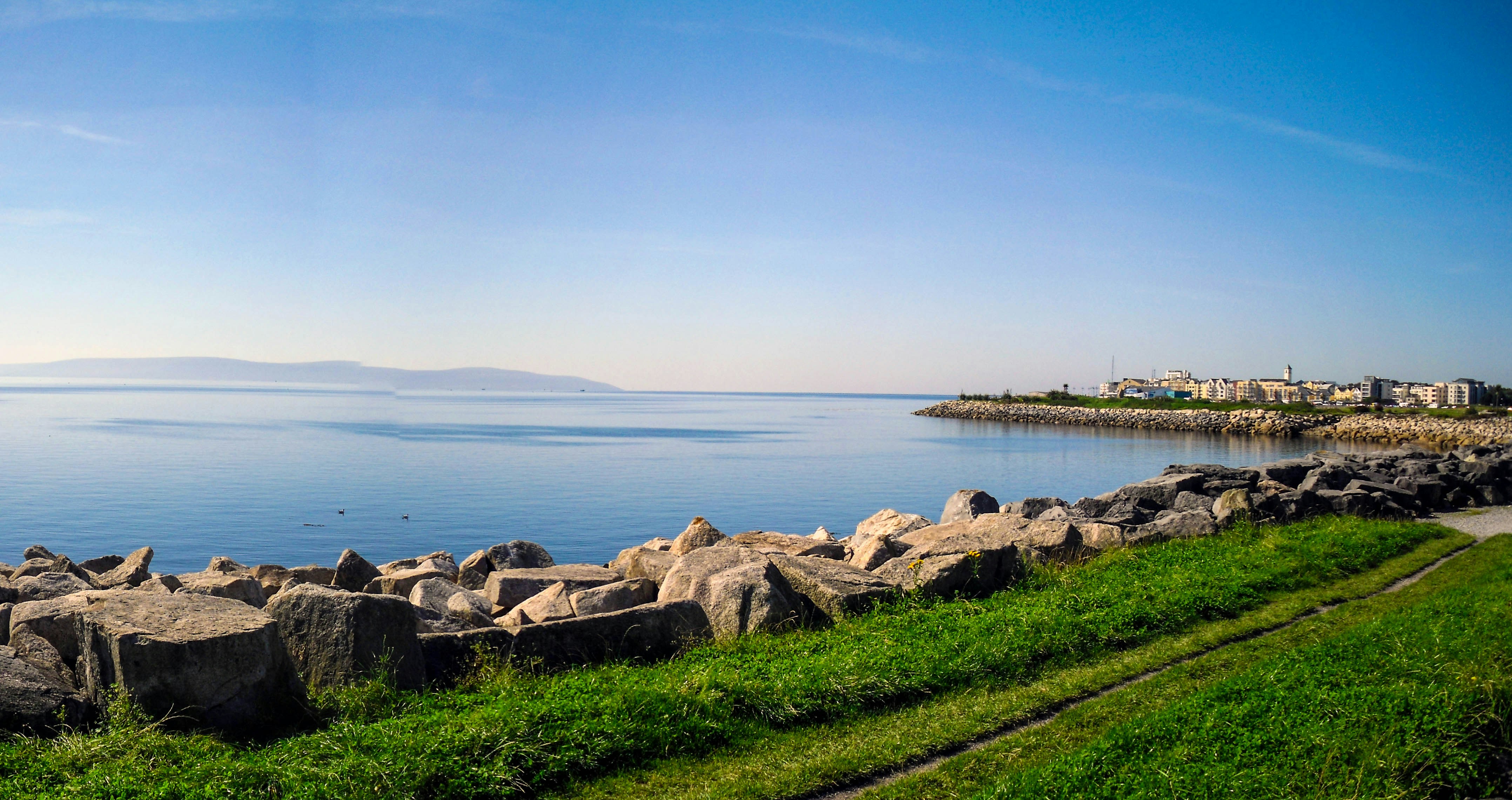 Um grande corpo de água sentado ao lado de um campo verde exuberante ...