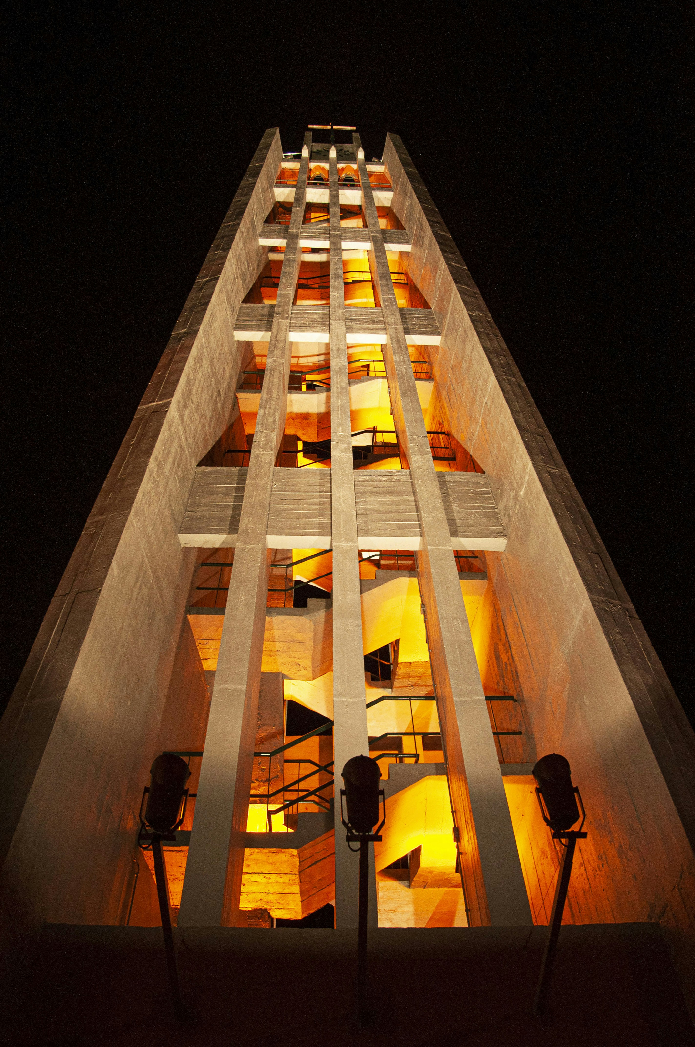 Amber Ascension: Night-lit Concrete Tower with Visible Stairwell