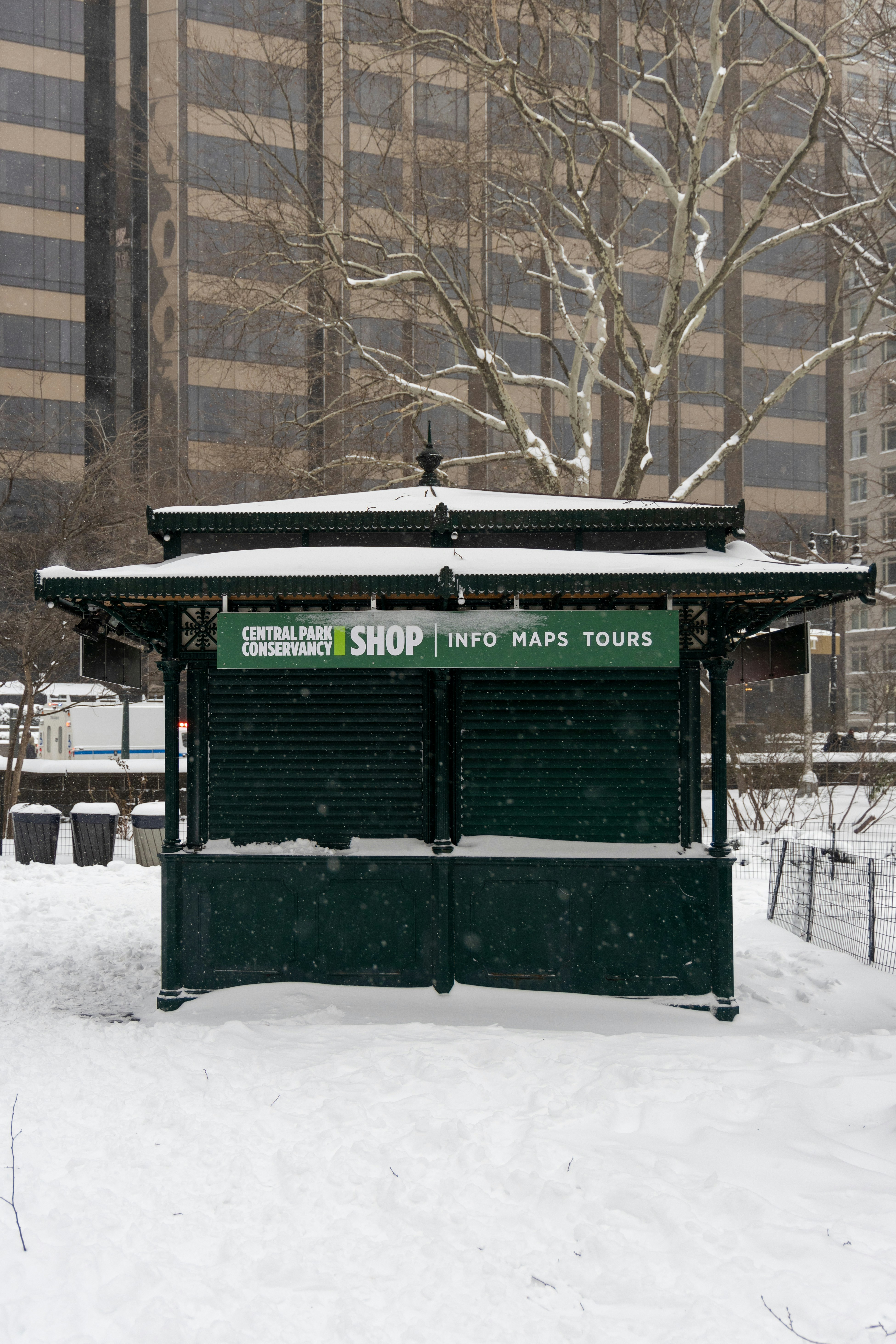 A bus stop covered in snow next to a tall building photo – Free New ...