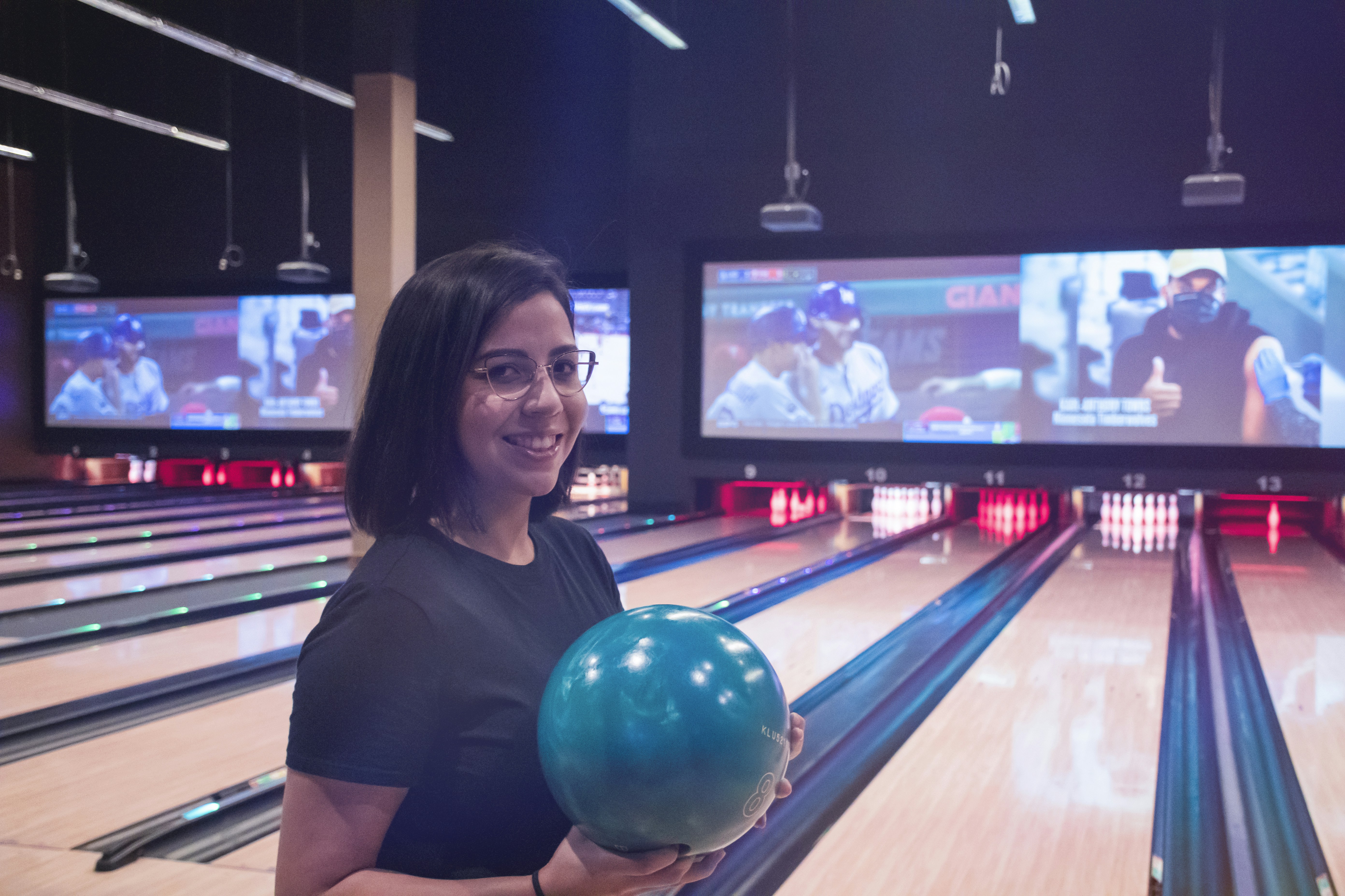 A woman holding a bowling ball in a bowling alley photo – Free Forney ...