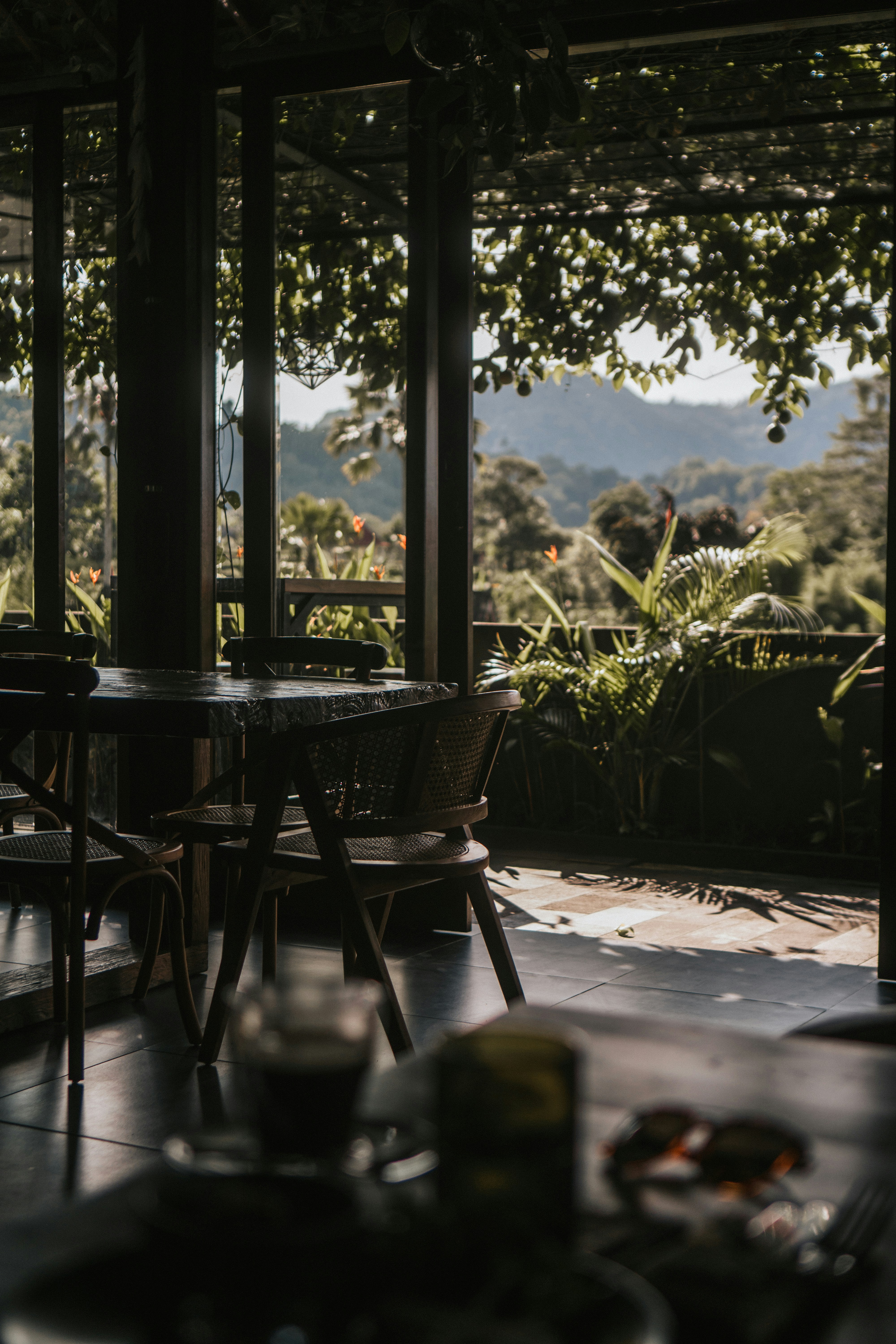 Cozy dining area framed by lush greenery and mountains in the background, inviting tranquility and connection with nature.