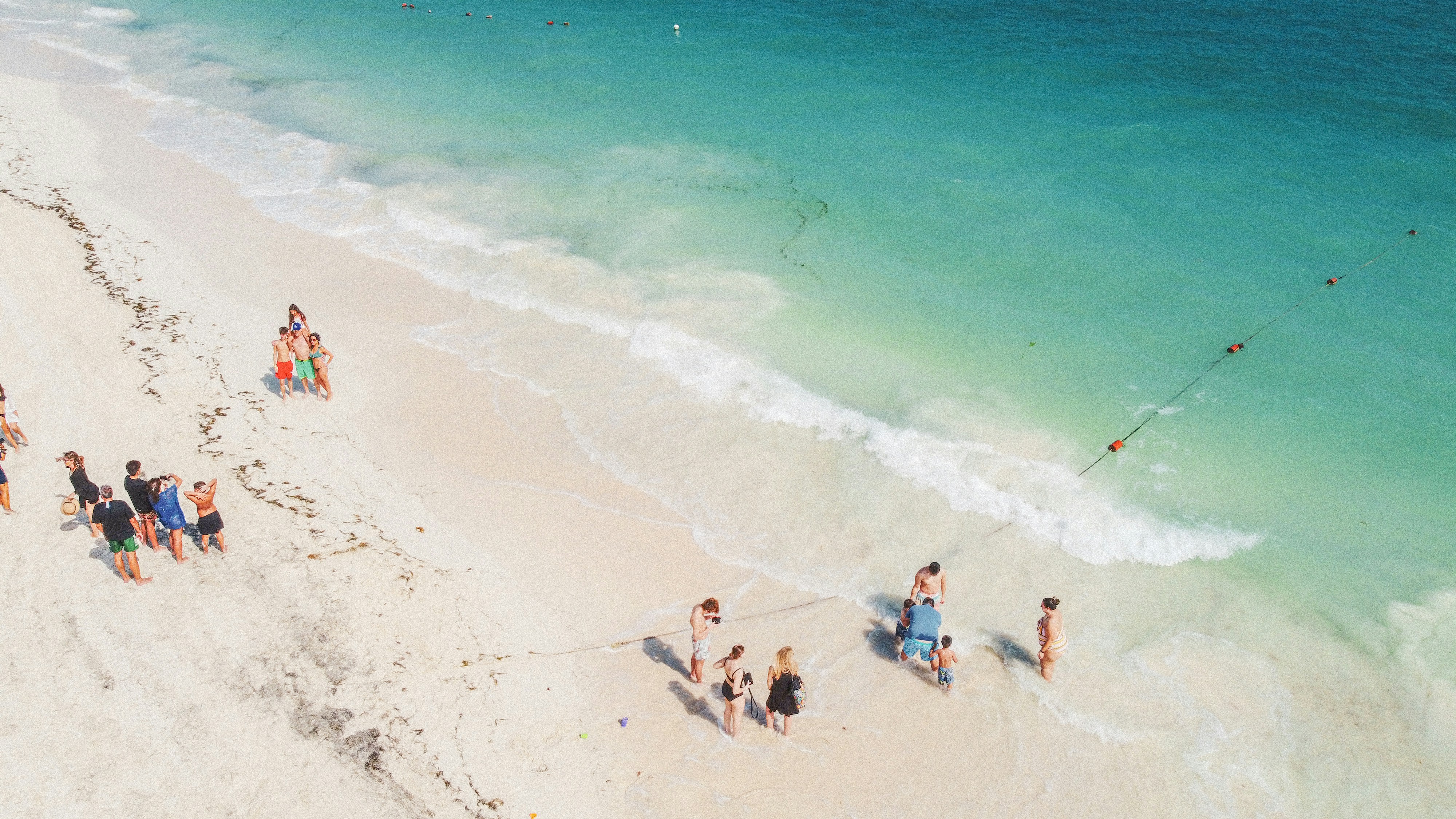 Eine Gruppe von Menschen, die auf einem Sandstrand stehen Foto ...