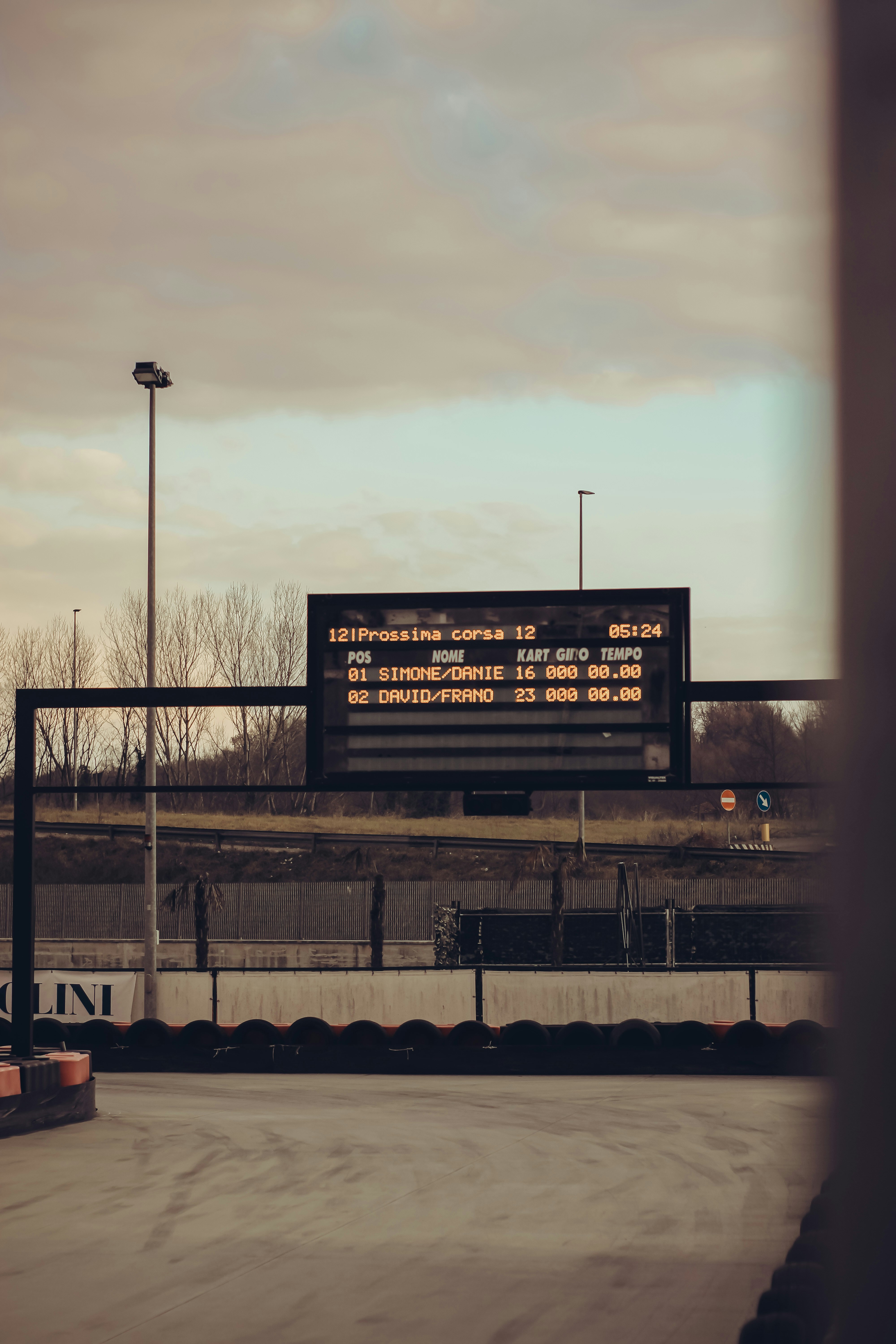 Electronic scoreboard over a quiet karting track at golden hour