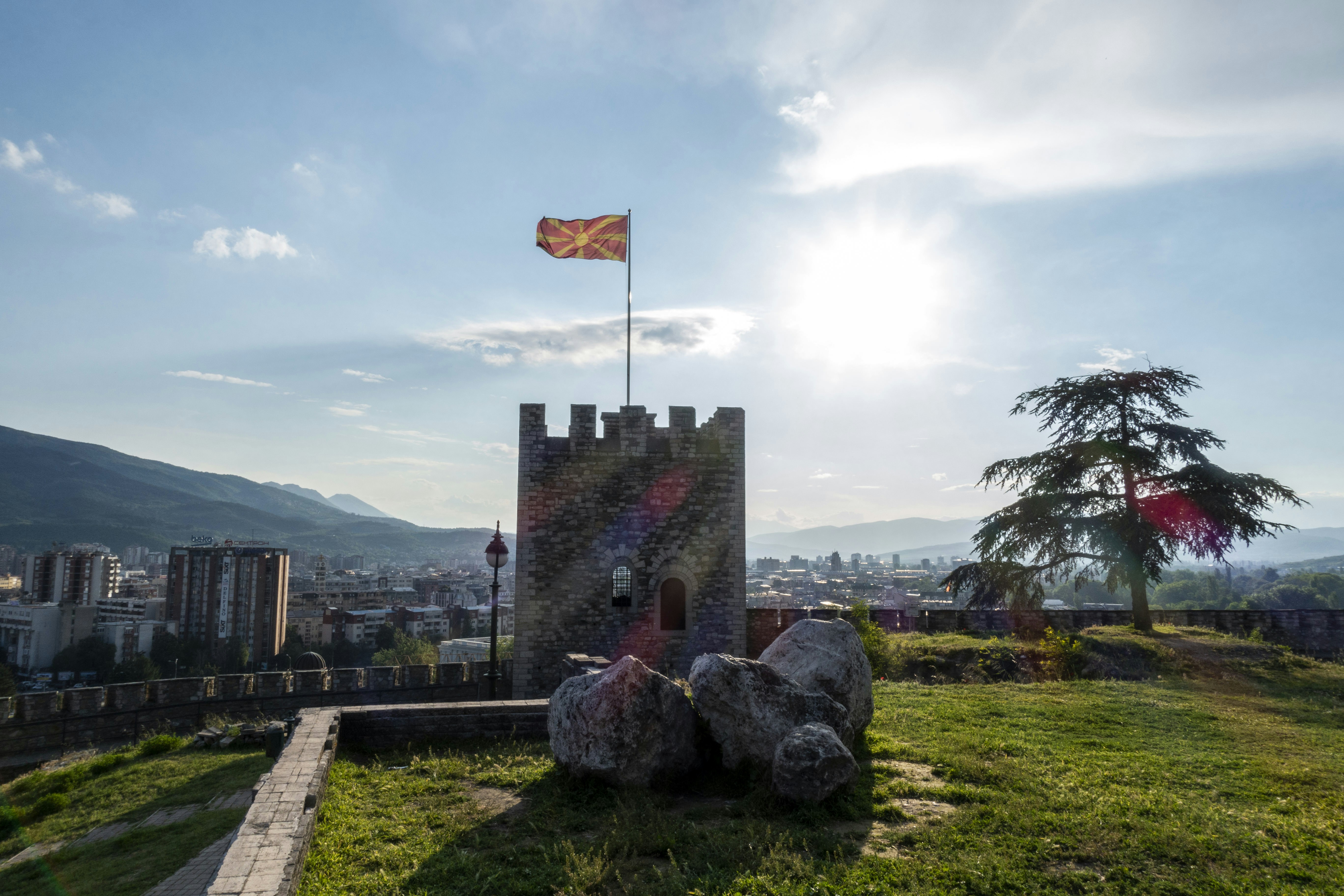 The flag of North Macedonia flying over the capital of Skopje. | a castle with a flag on top of it