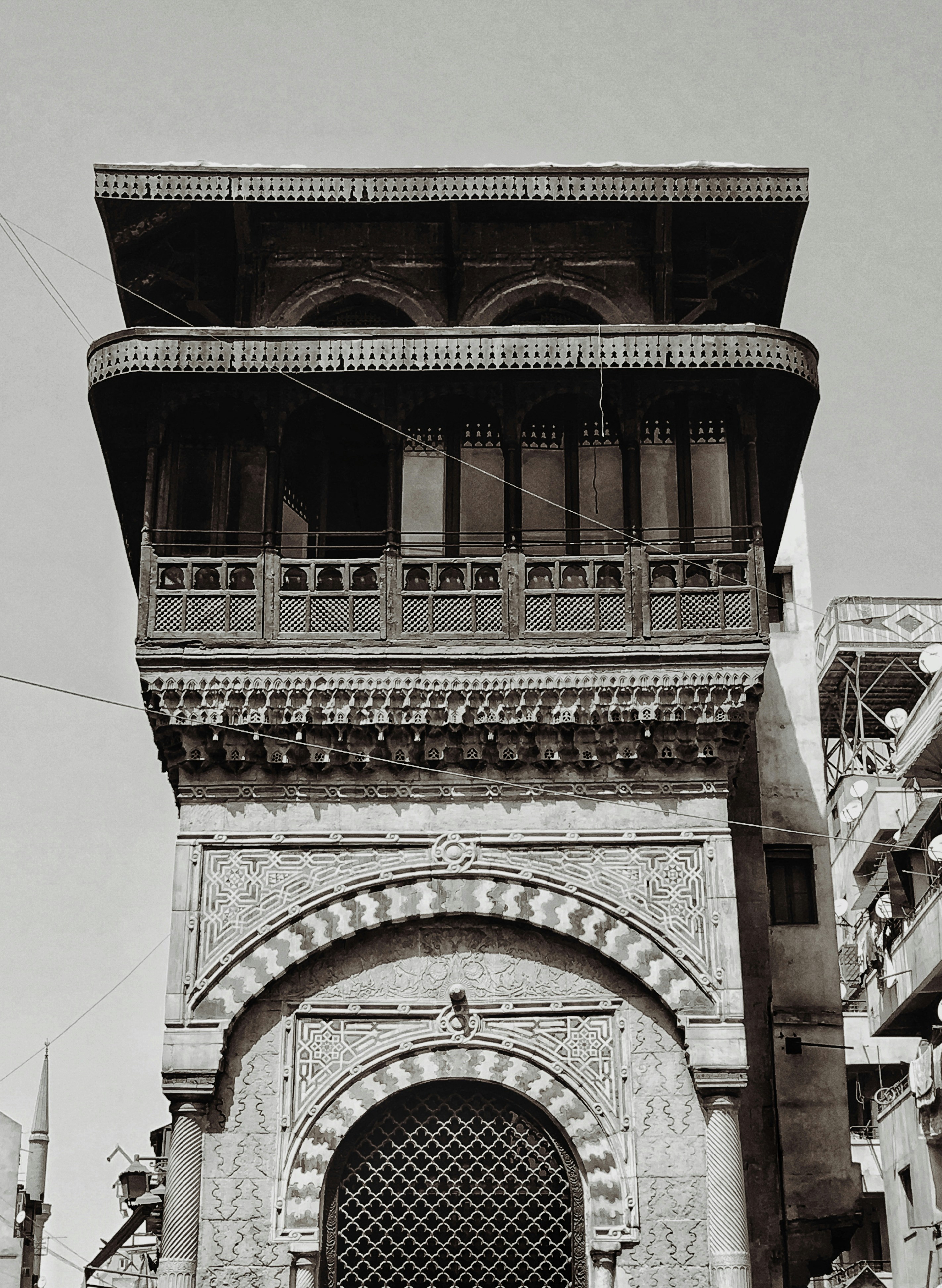 Ornate historical building facade with detailed arches and intricate latticework under a clear sky.